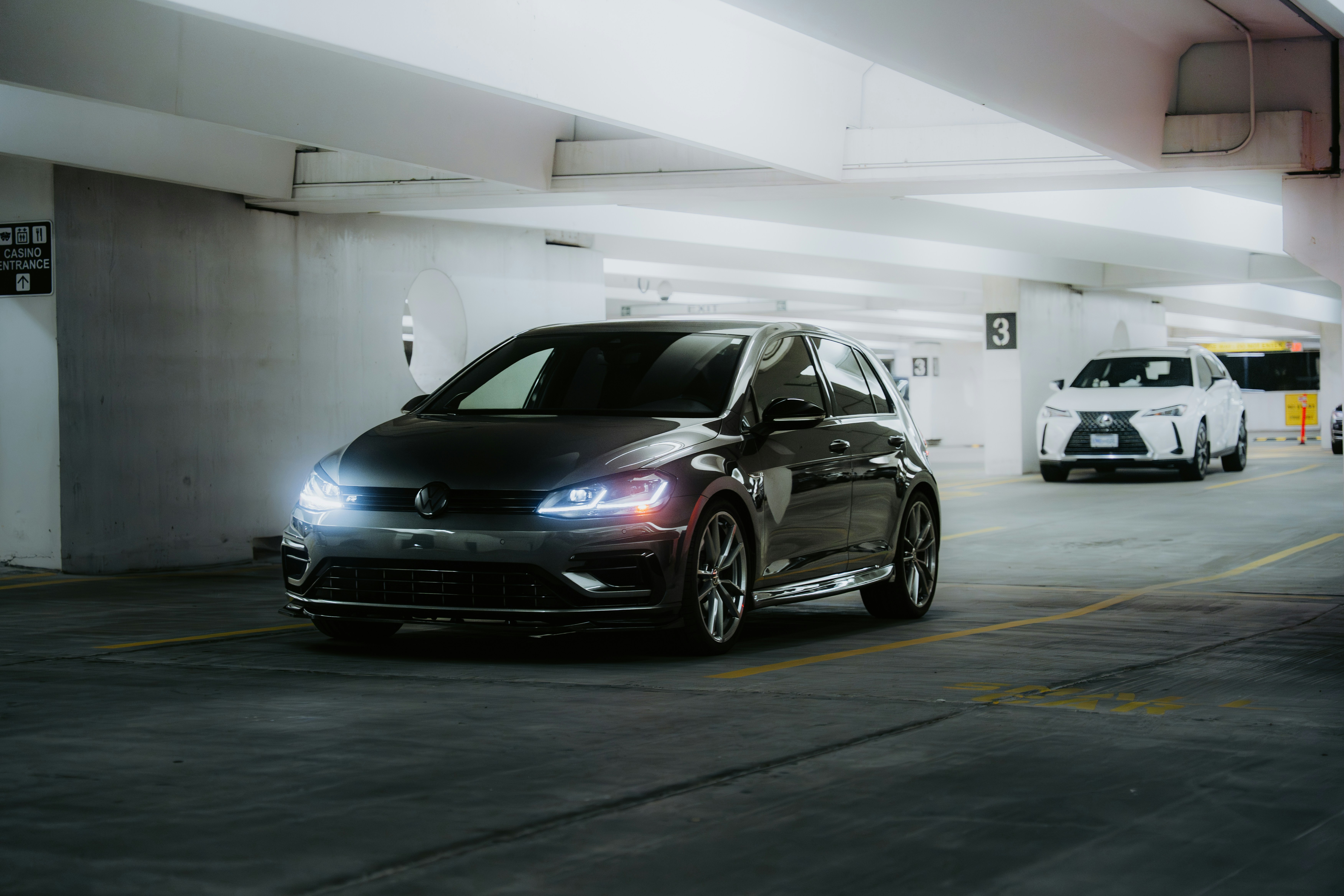 Sleek black hatchback parked in a dimly lit parking garage, showcasing its modern design and illuminated headlights.