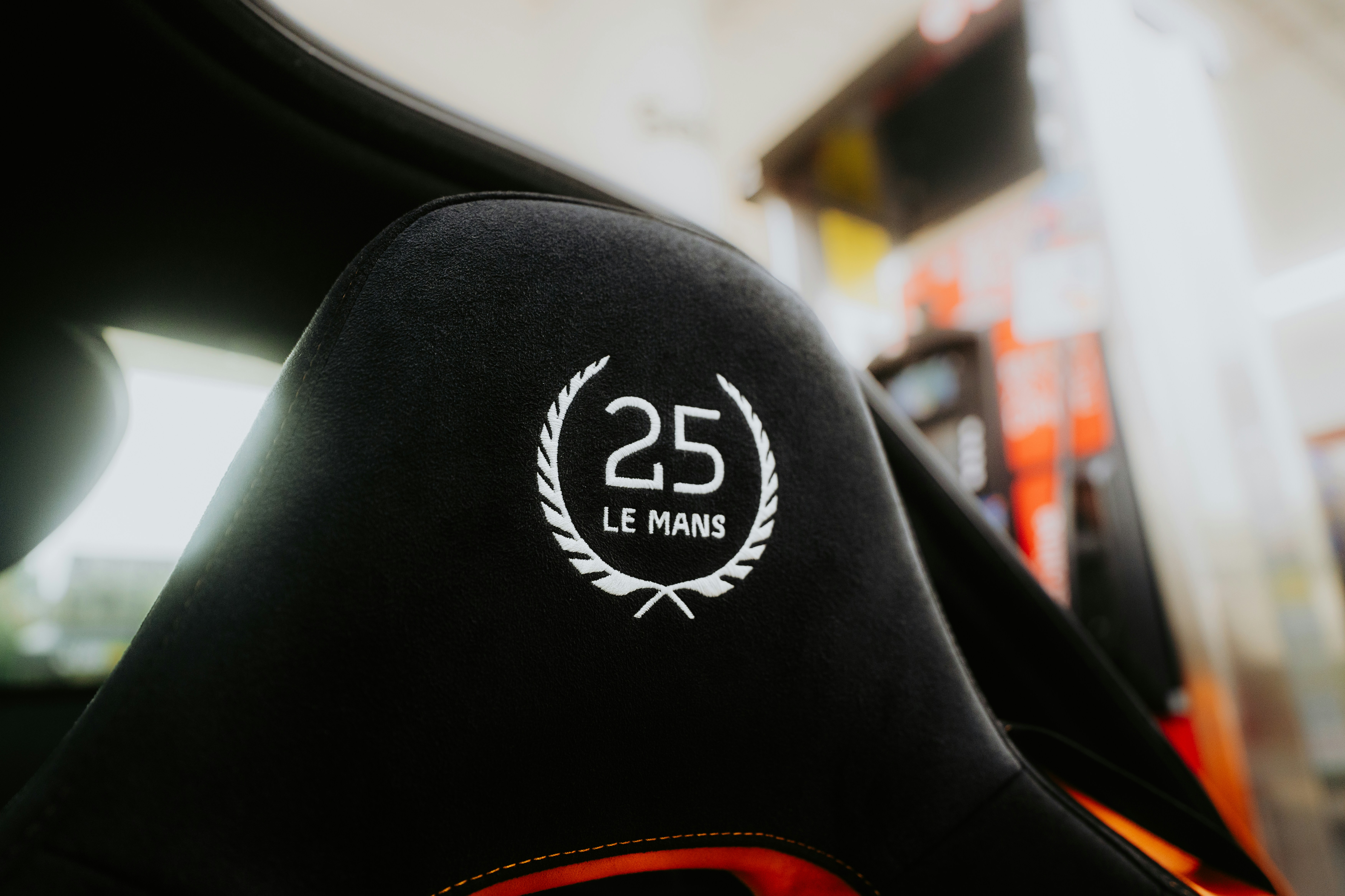 Embroidered '25 le mans' logo on a black car seat.