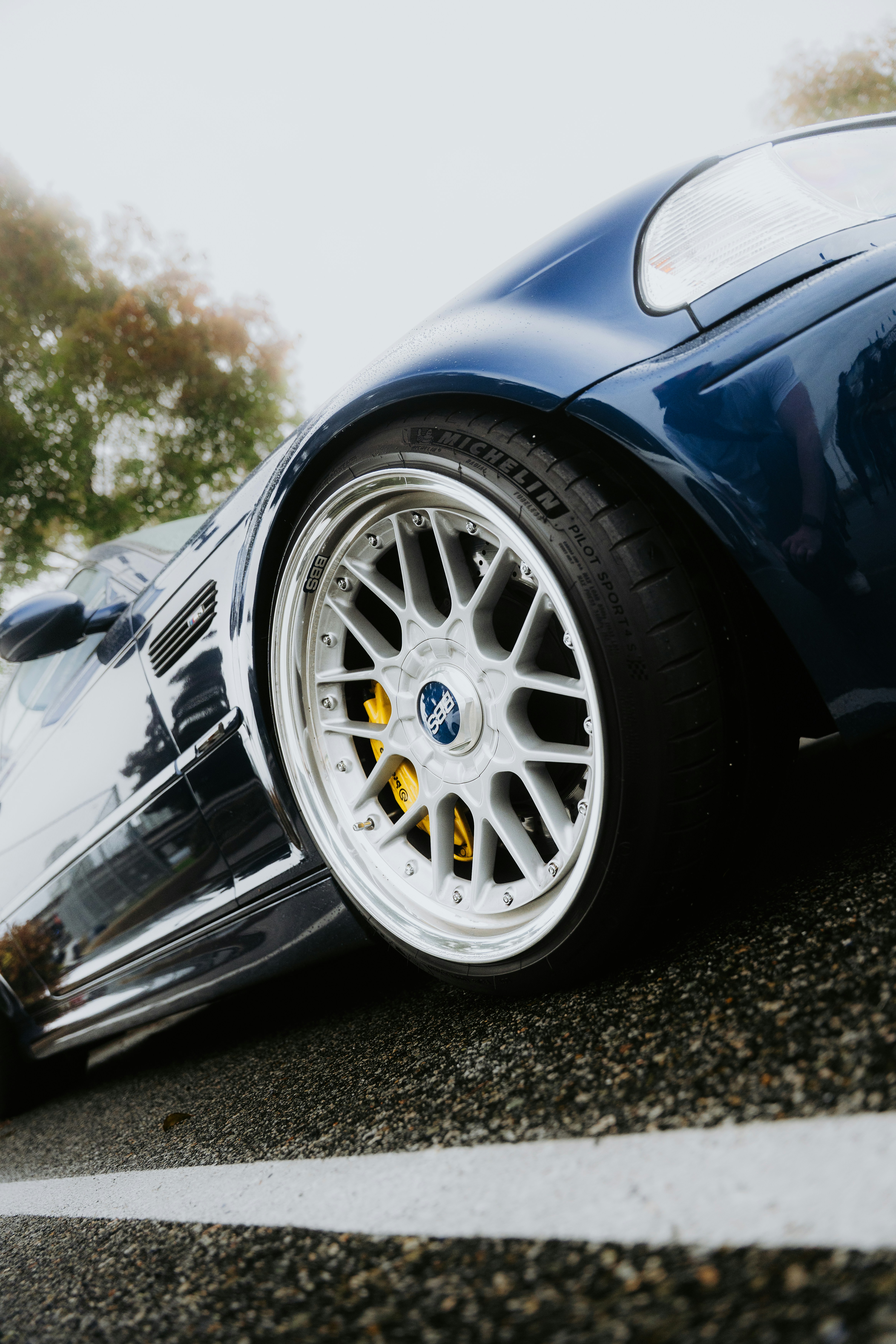 Close-up of a sleek car wheel showcasing intricate design and vibrant brake calipers. The setting highlights the vehicle's performance and aesthetic appeal.