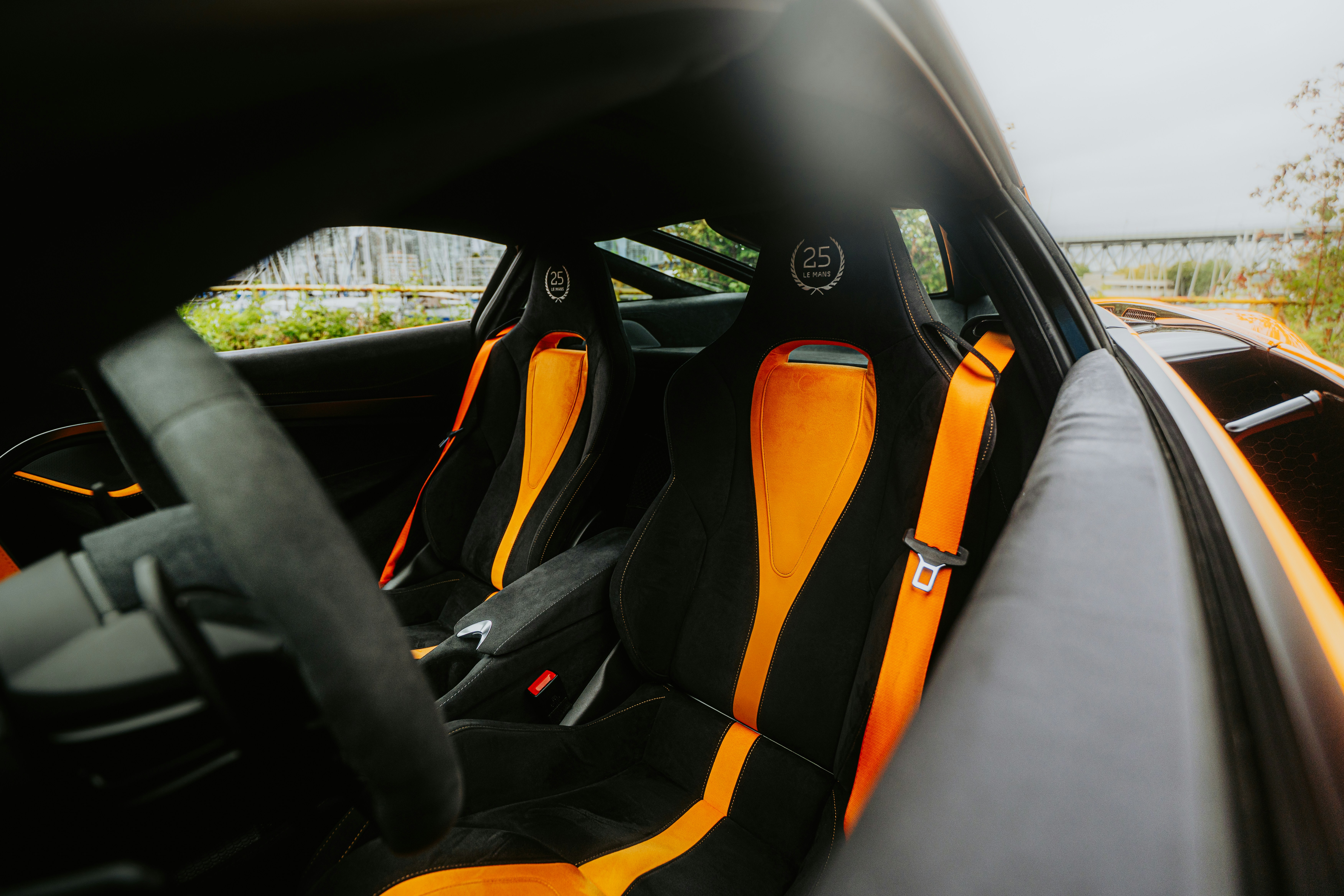 Sleek sports car interior featuring black and orange racing seats, showcasing a blend of comfort and dynamic design.