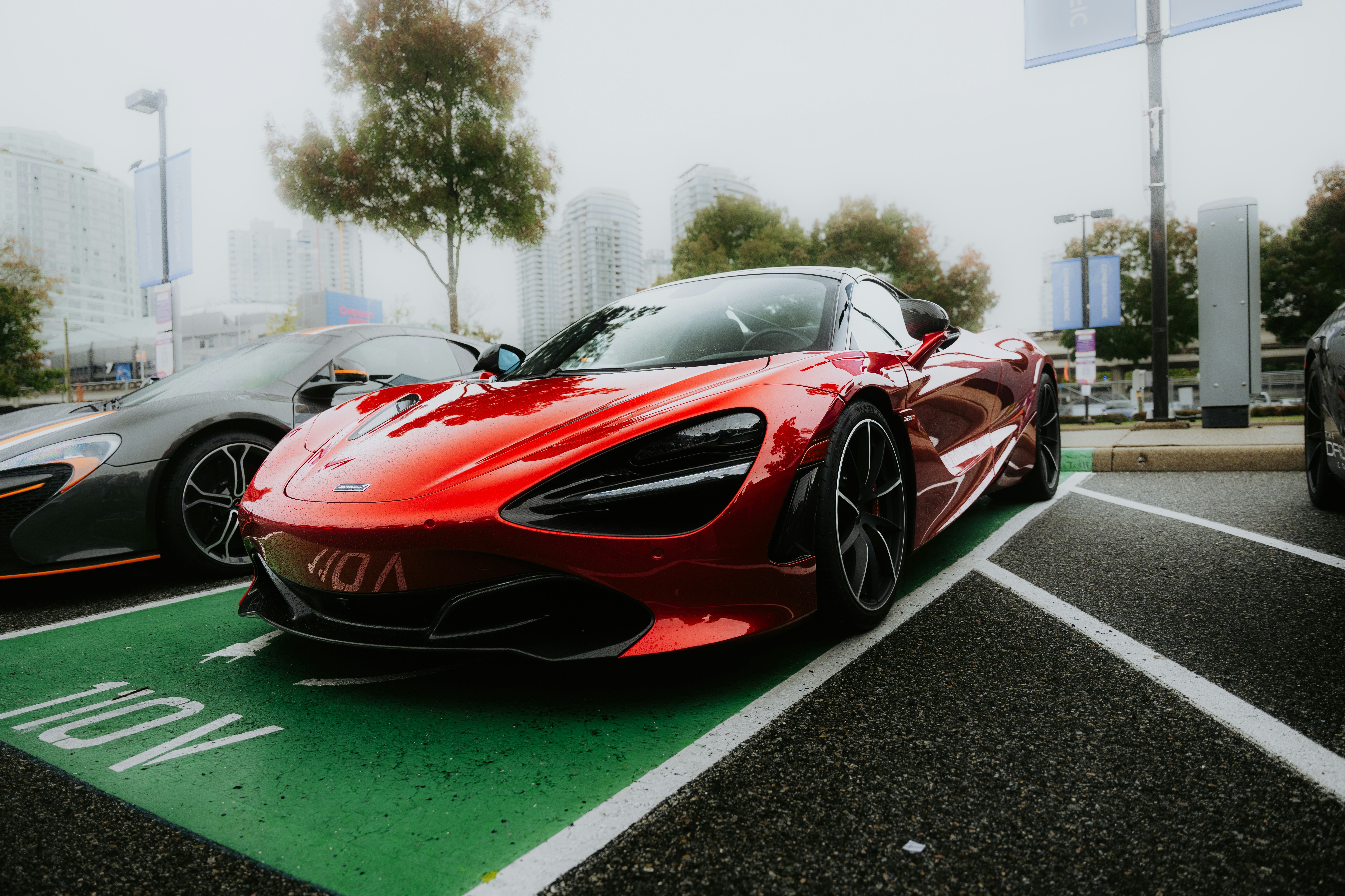 Sleek red McLaren 720S parked prominently in a modern urban setting, showcasing its aerodynamic design and luxury features.