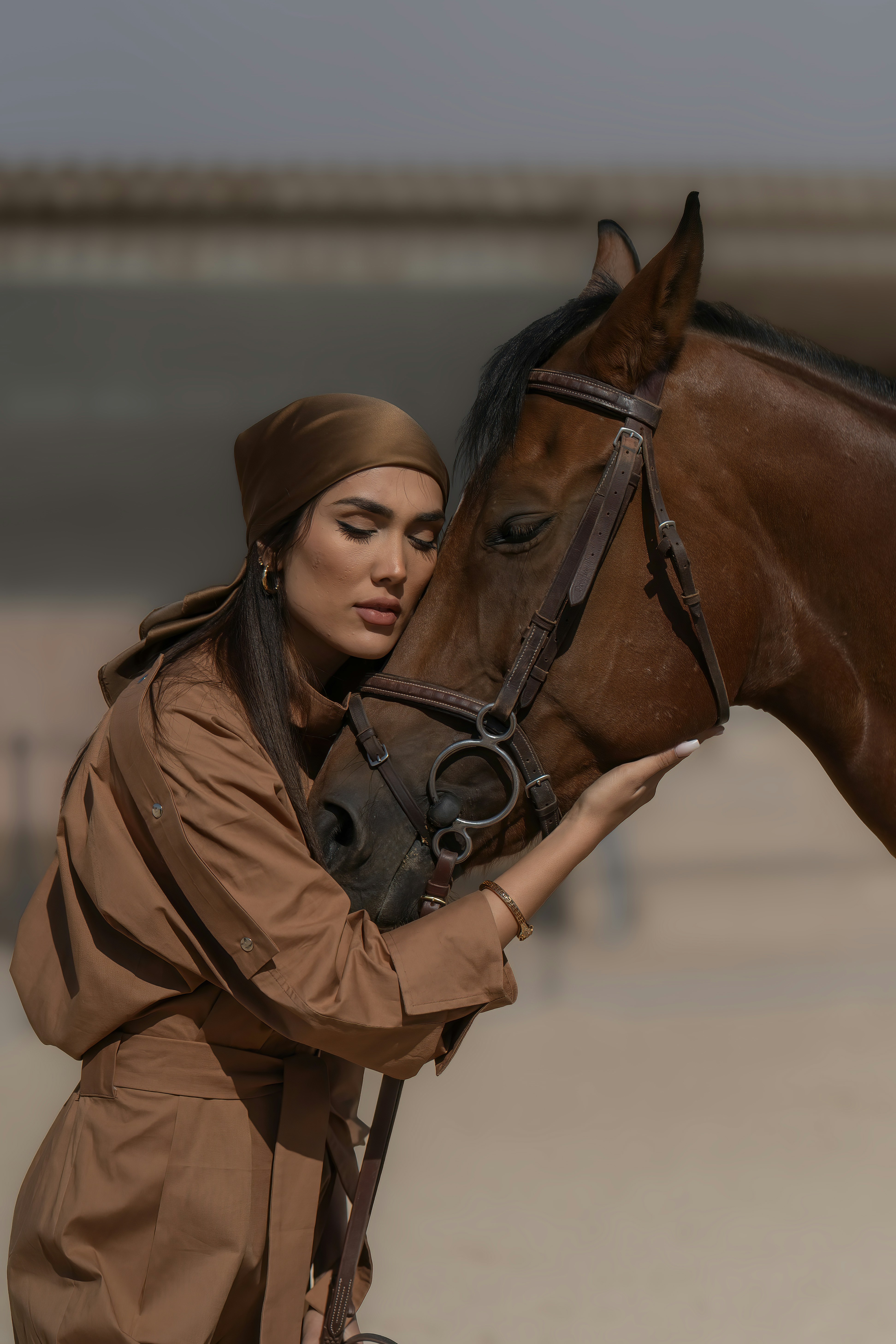 Woman in brown clothing embracing a brown horse