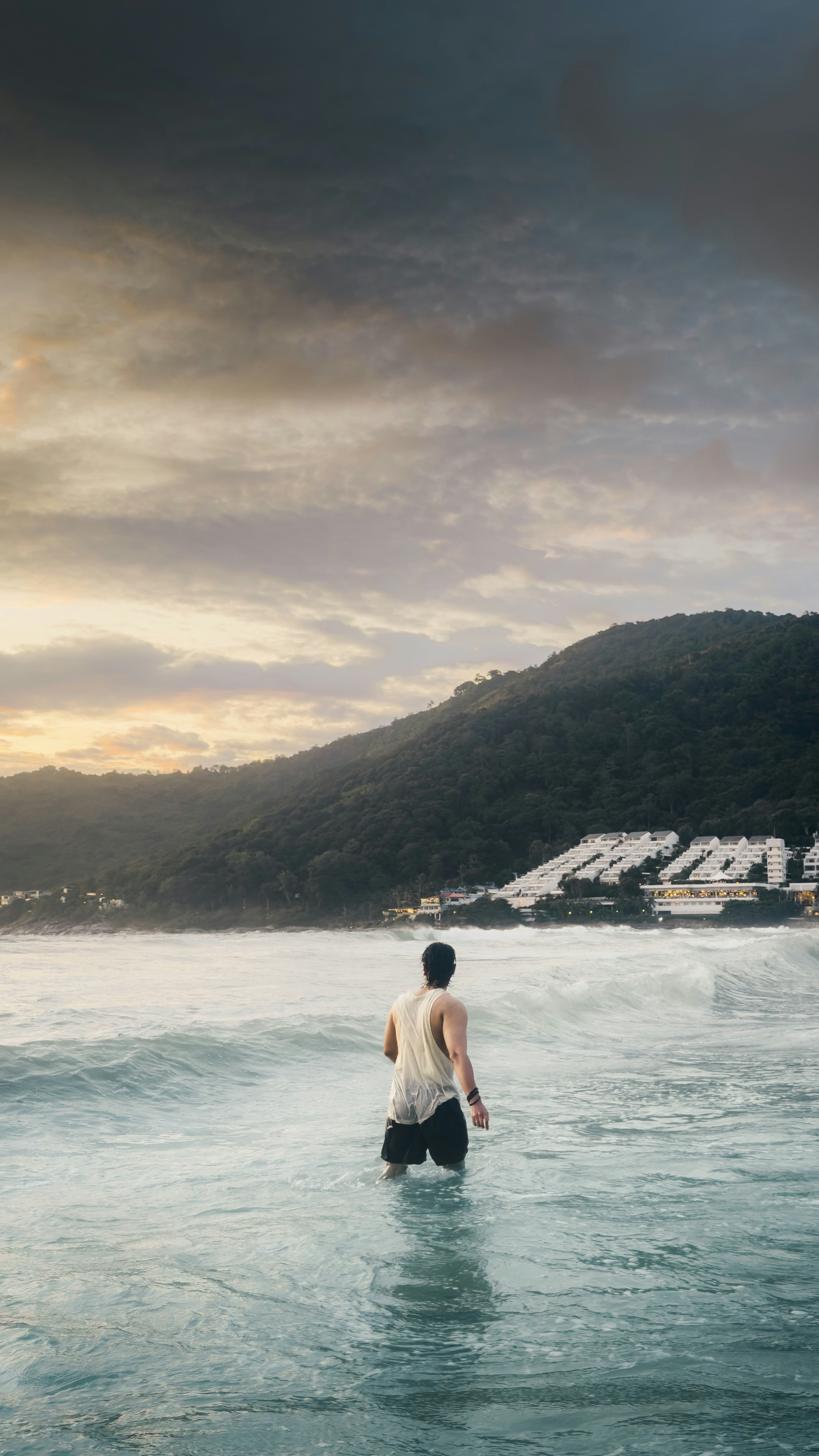 Sunset in the Surf: A lone swimmer against a hillside resort