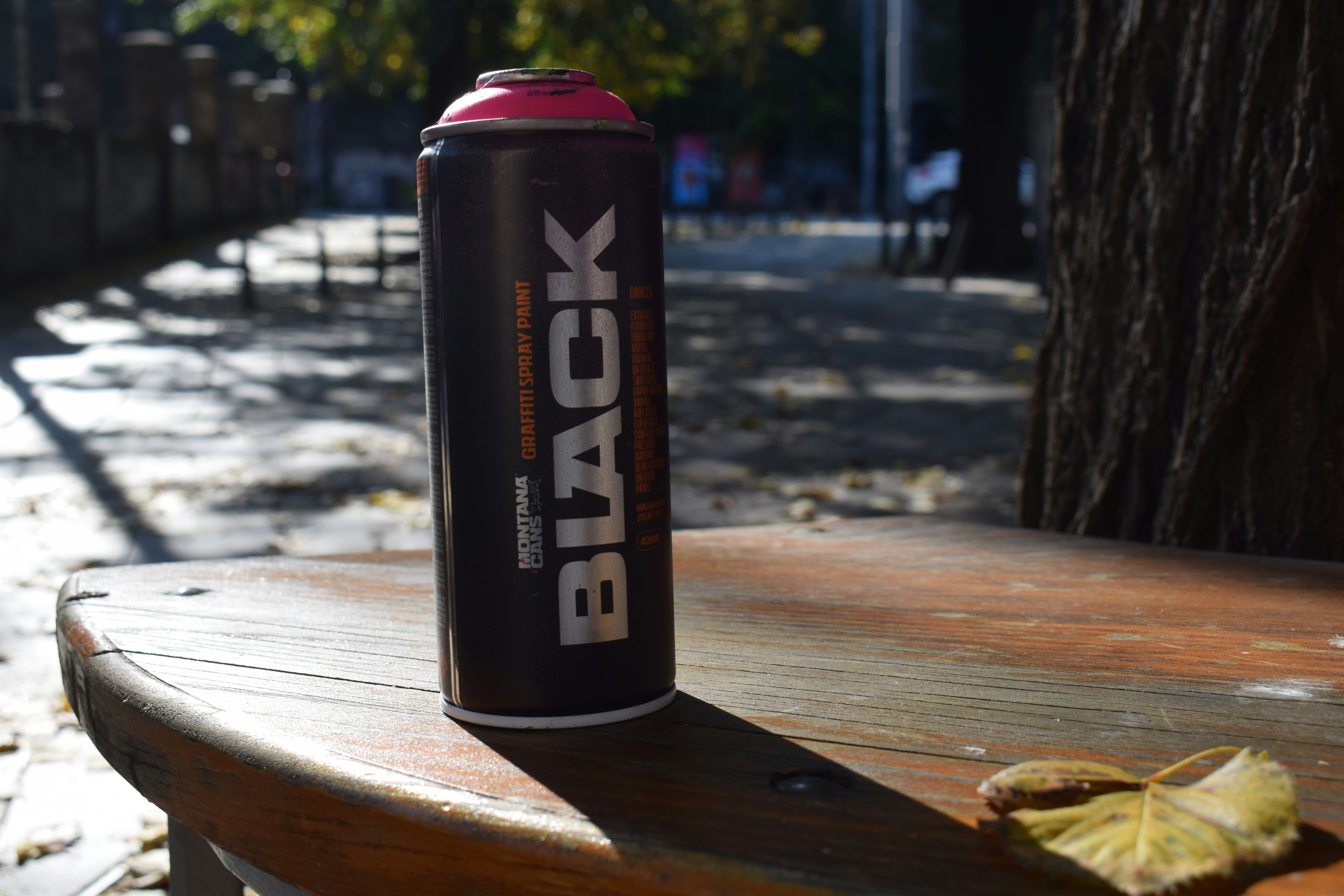Black spray paint can on a wooden surface outdoors table.