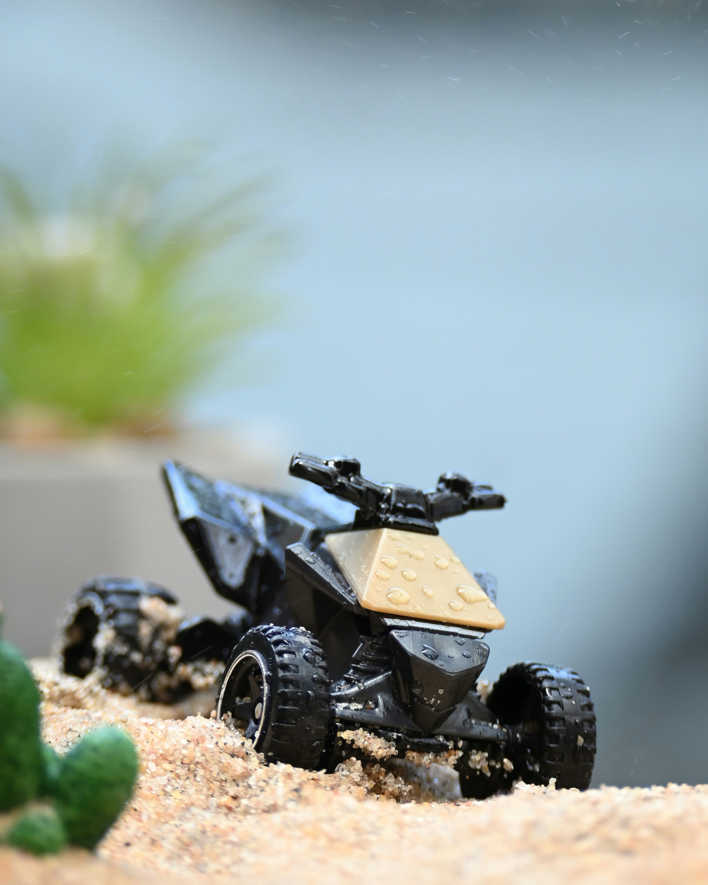 A black toy atv on a sandy surface.