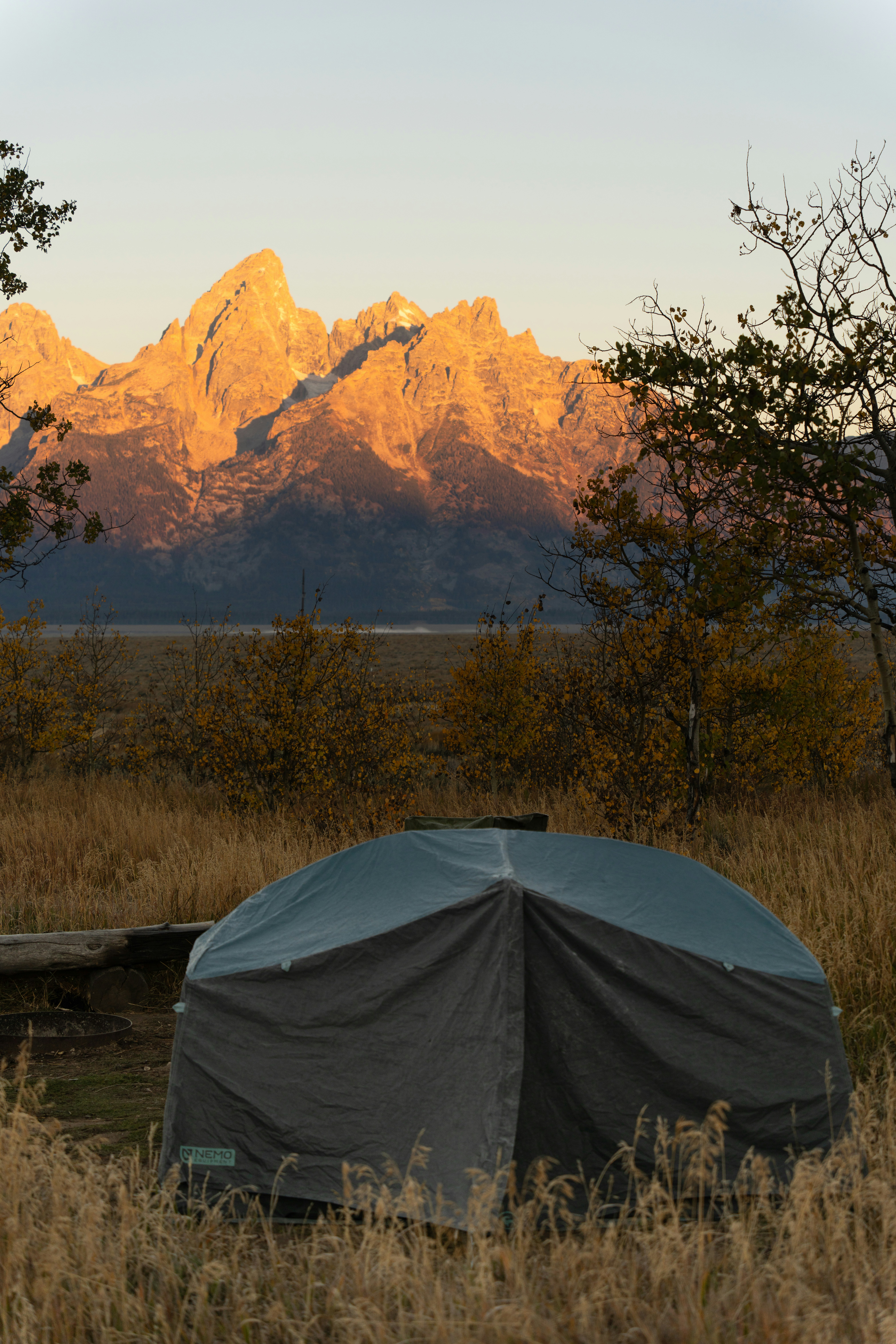 Tent in field with mountains at sunrise