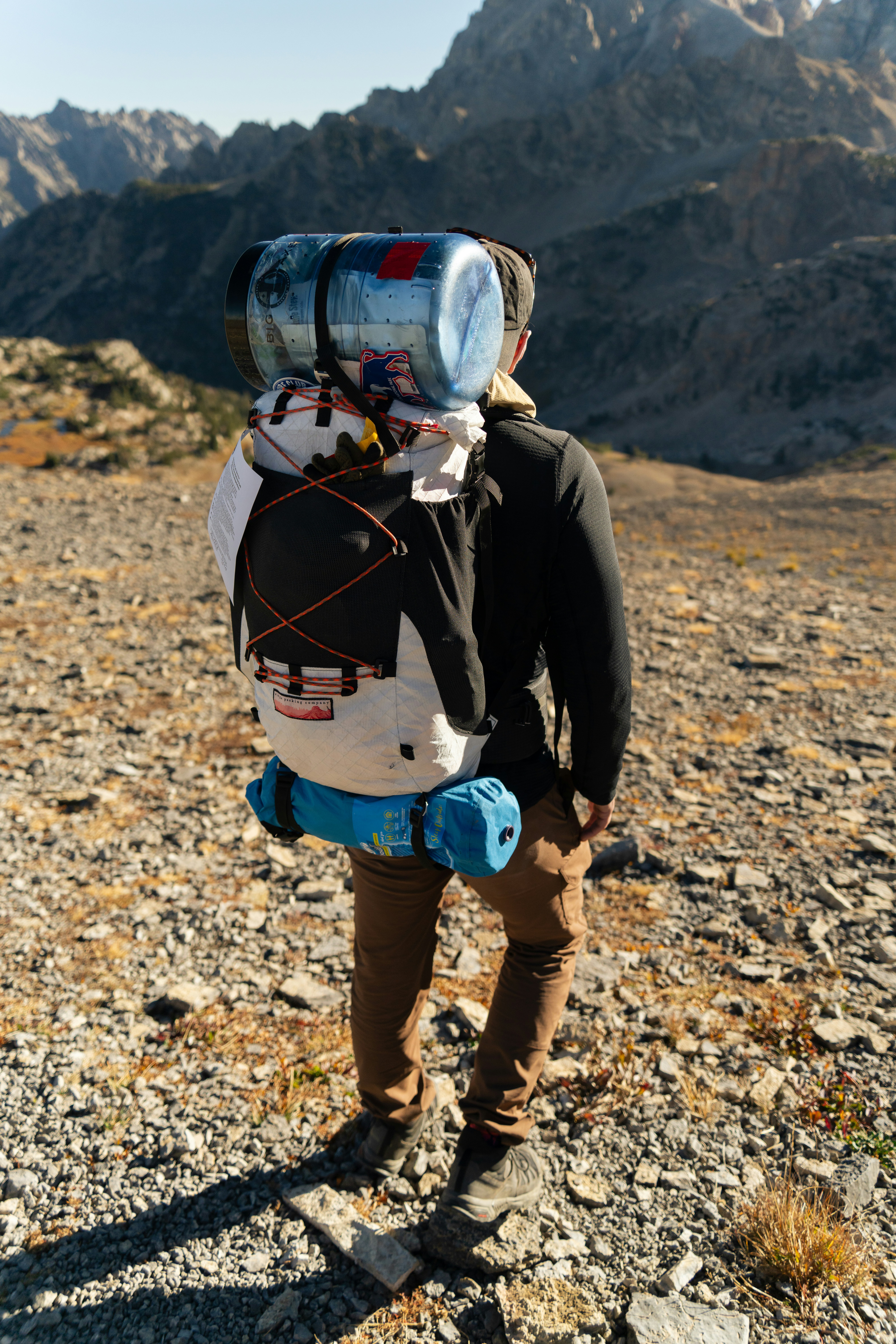 Ridgebound Carrier: A Mountaineer Balancing a Weathered Canister Across Jagged Peaks