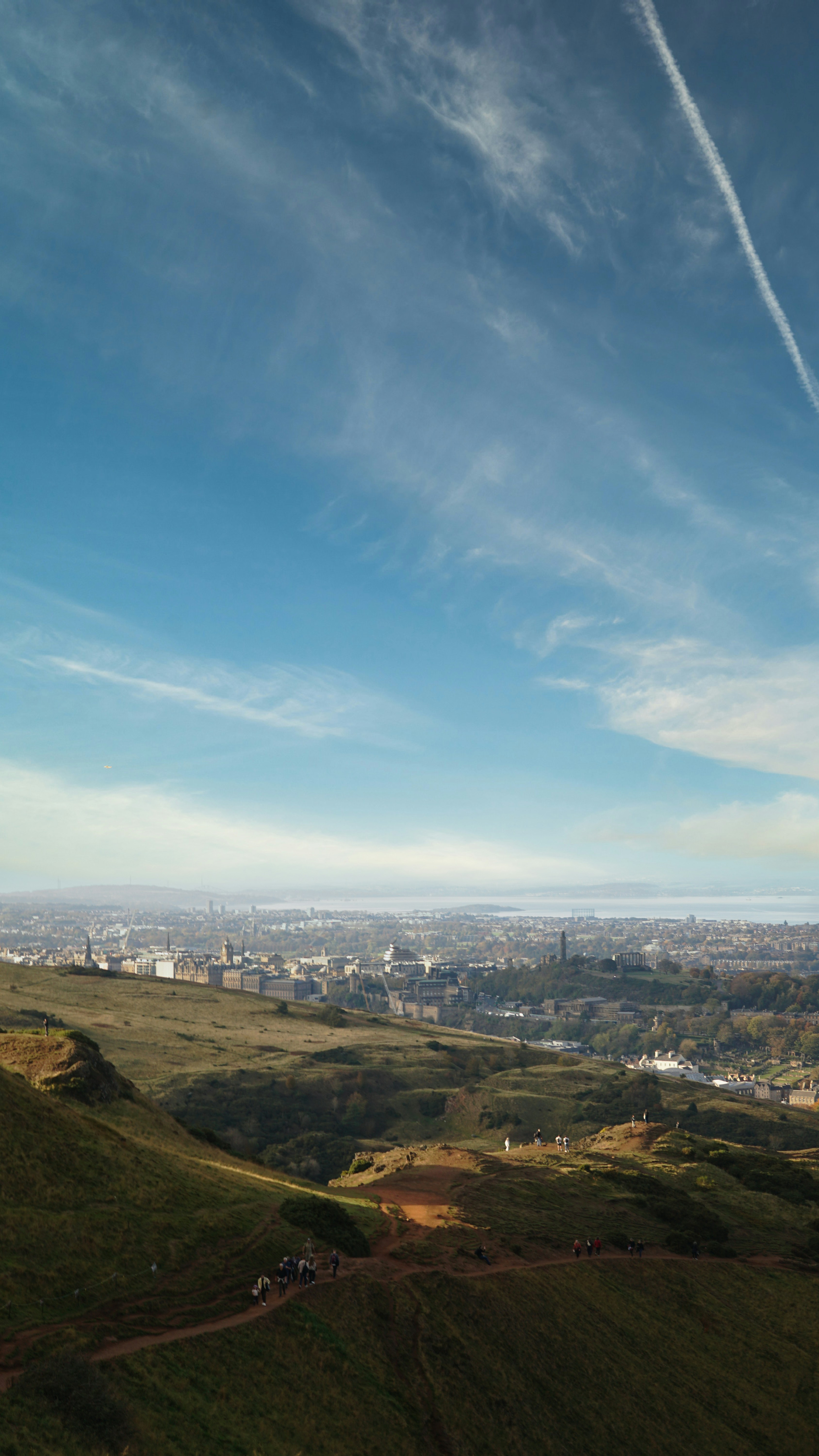 Paisaje urbano visto desde colinas cubiertas de hierba bajo un cielo ...