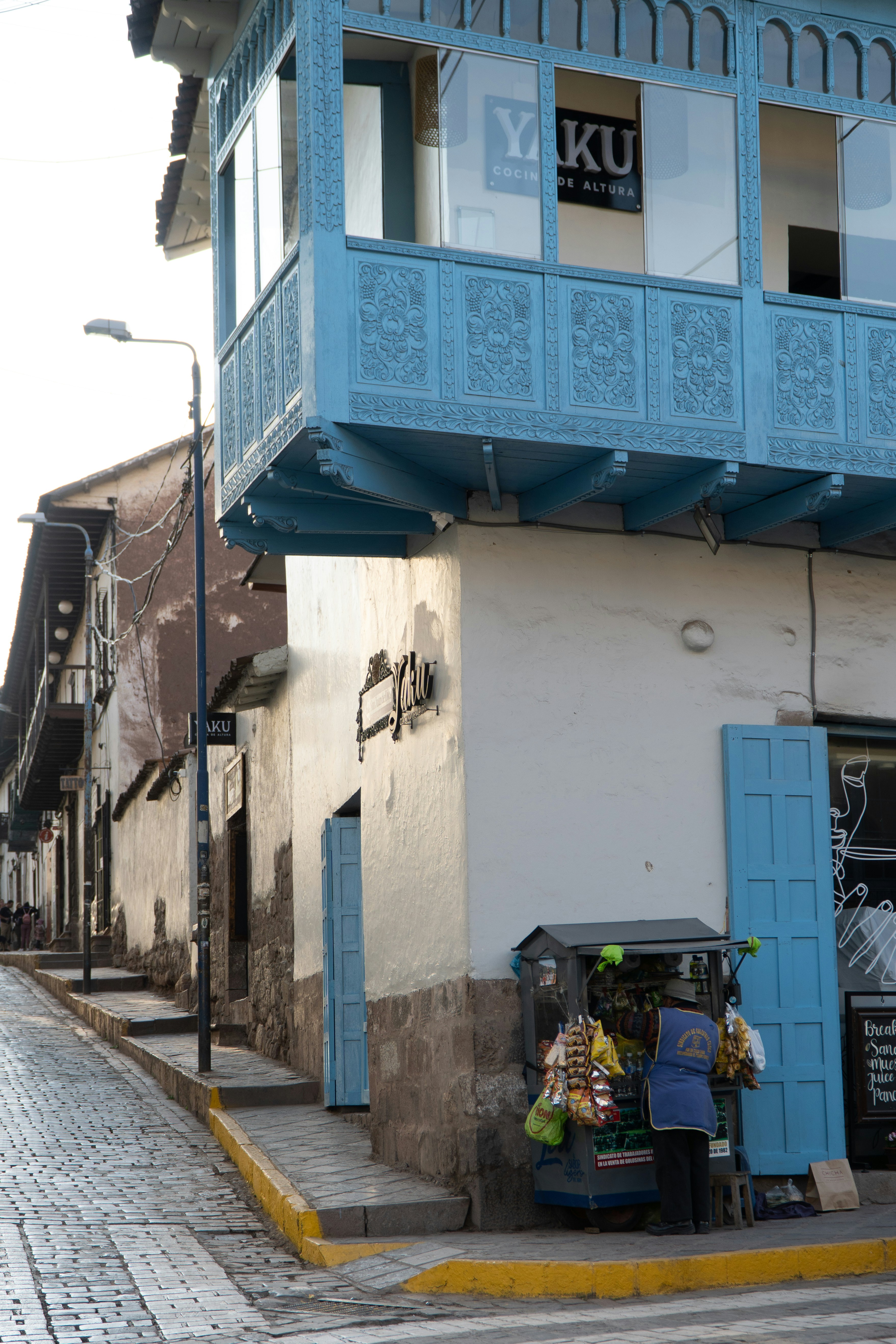 Carved Blue Veranda Overhang Framing a Cobblestone Street Market