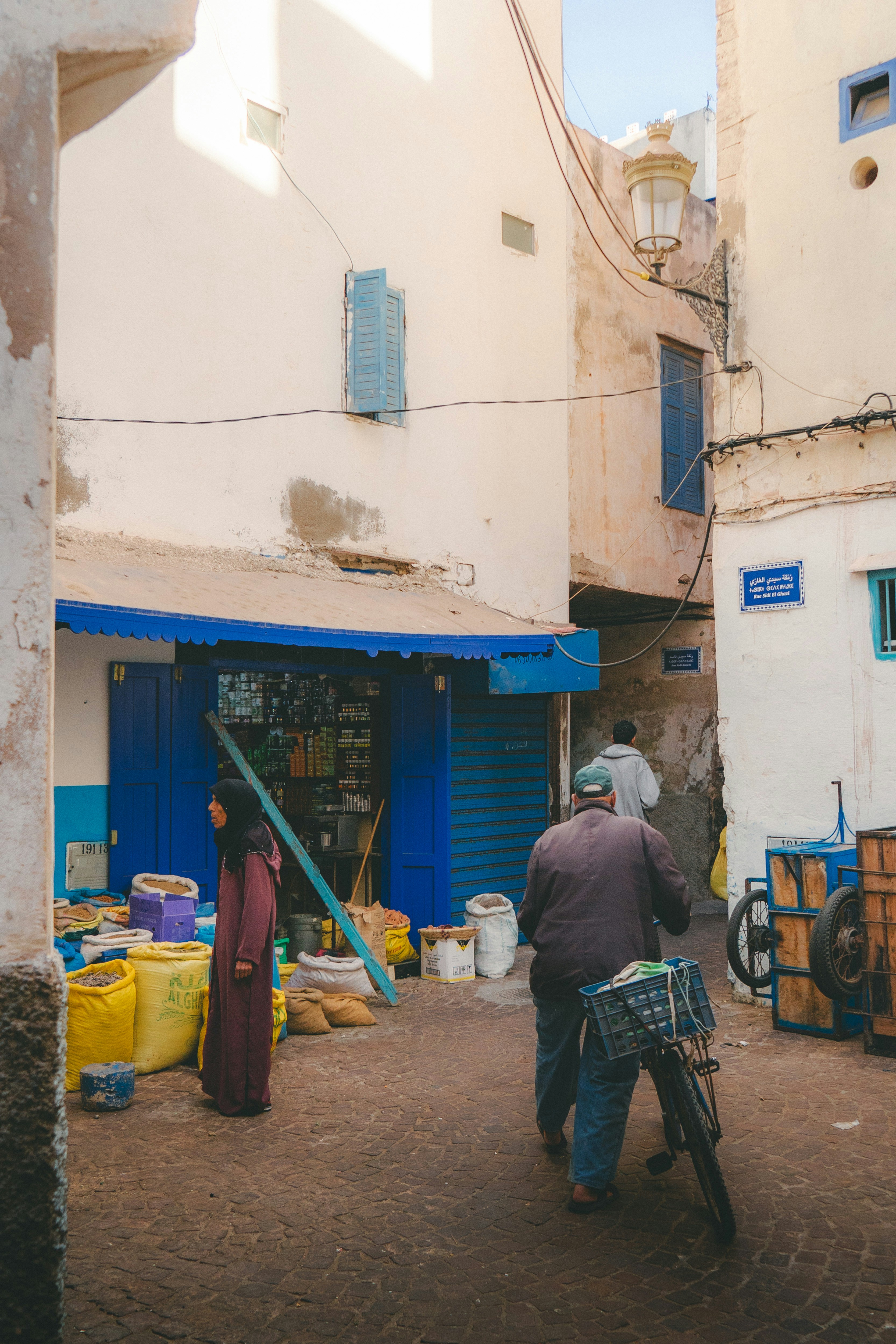 Blue Doors, White Walls: A Hum of Daily Trade in a Narrow Alley