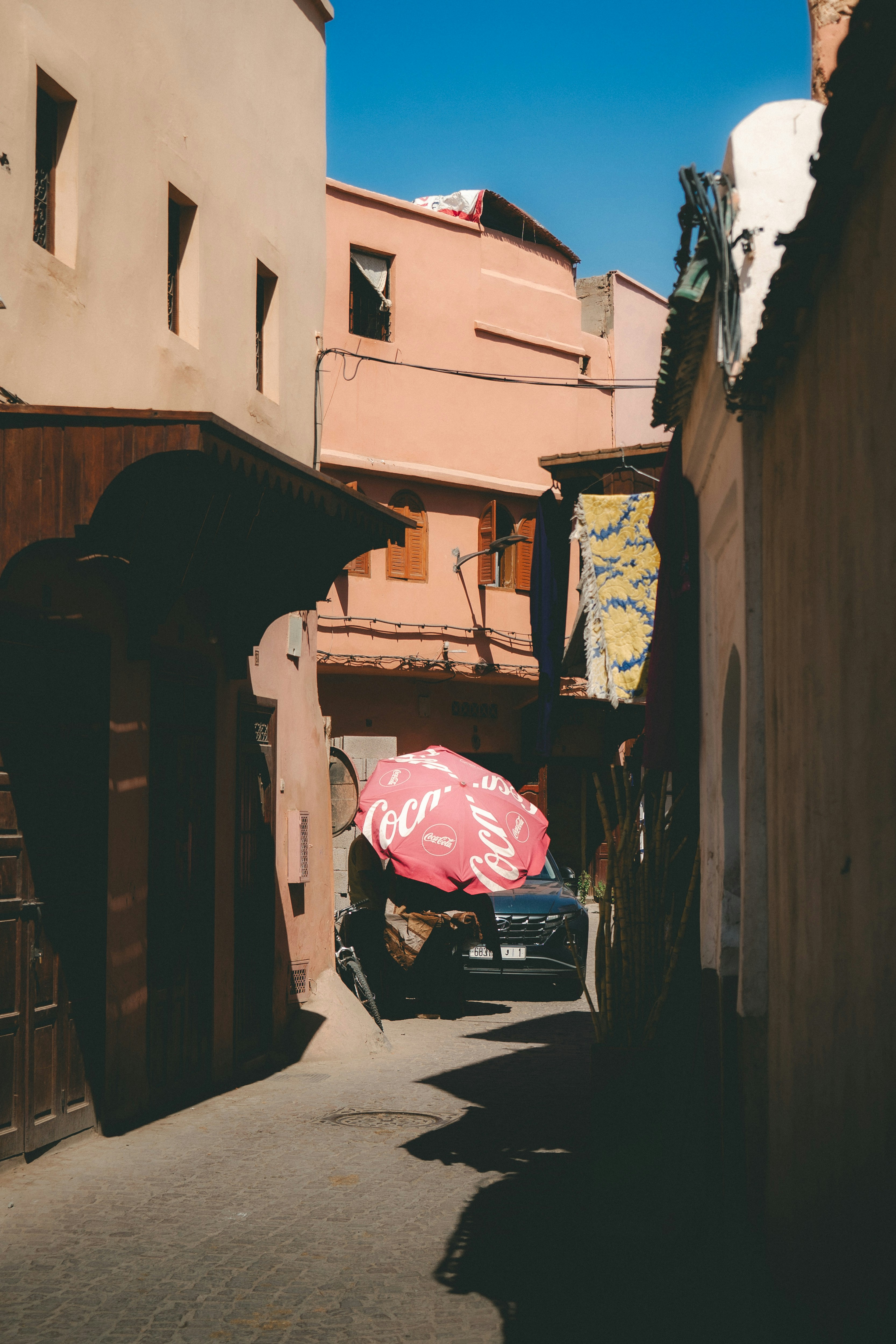 Scarlet Umbrella in a Sun-Burnished Narrow Alley