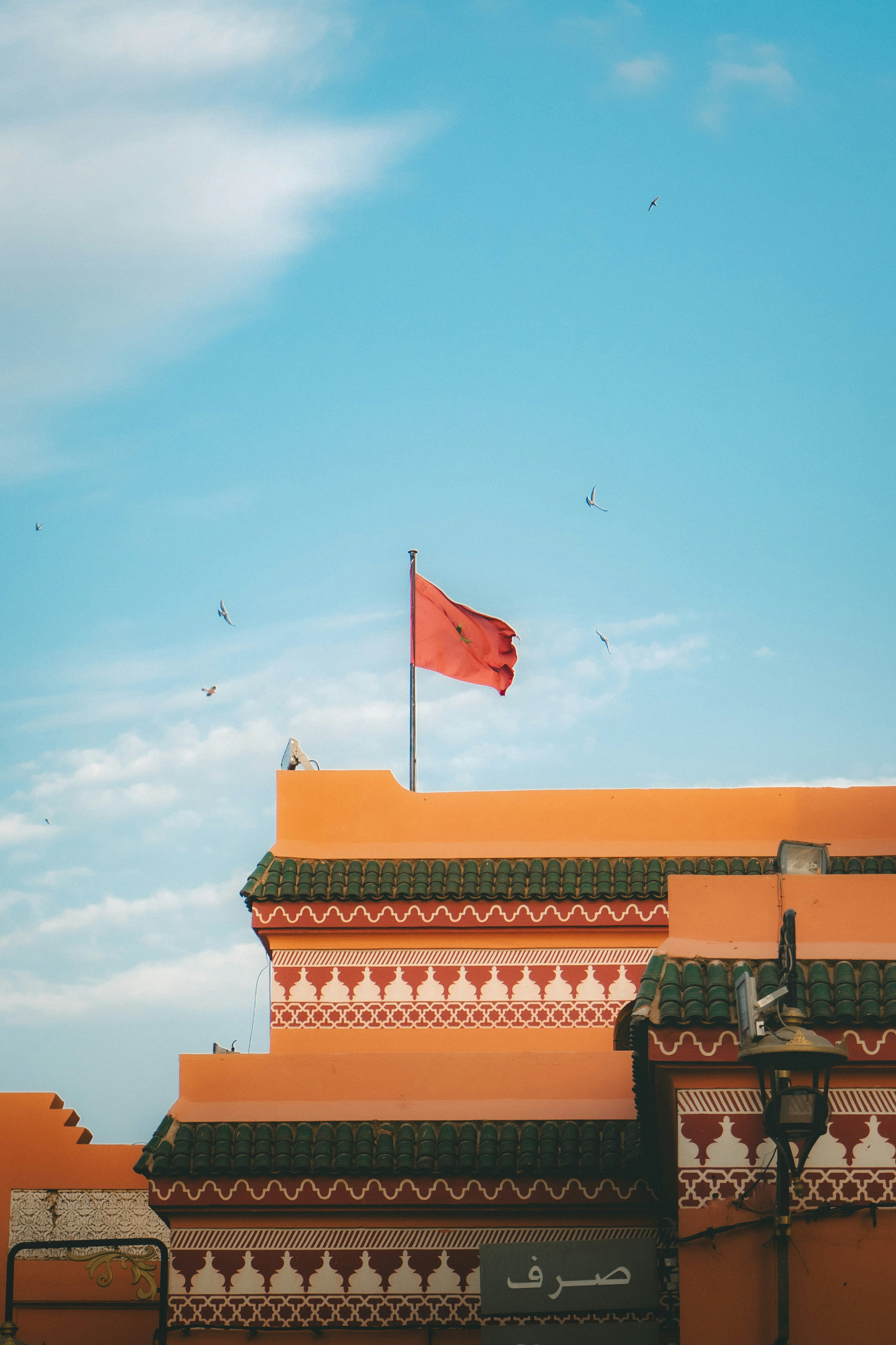 Red flag atop a building with ornate details.
