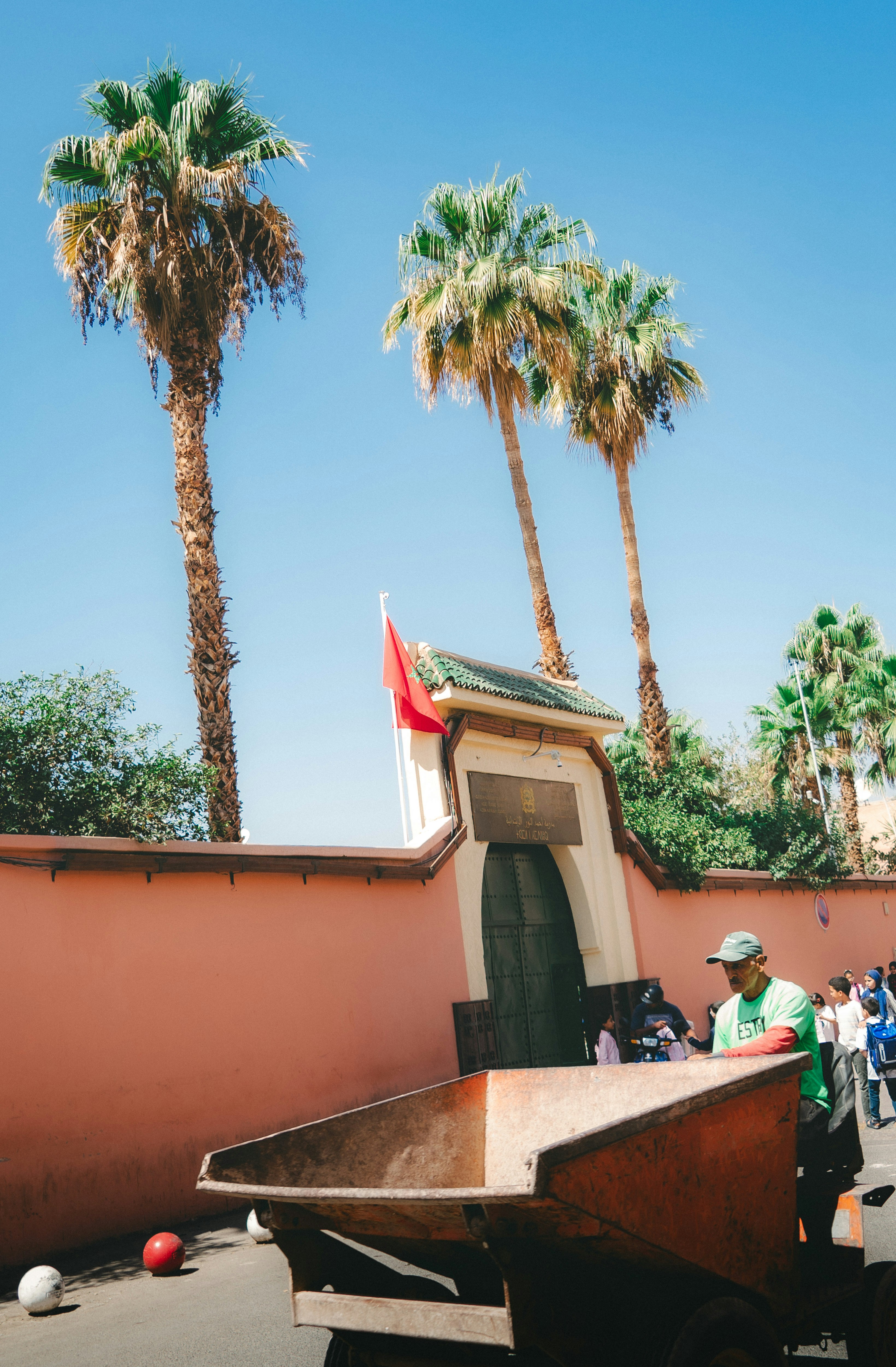 Gatehouse under Palm Canopies: A Peach-Walled Scene with a Red Flag