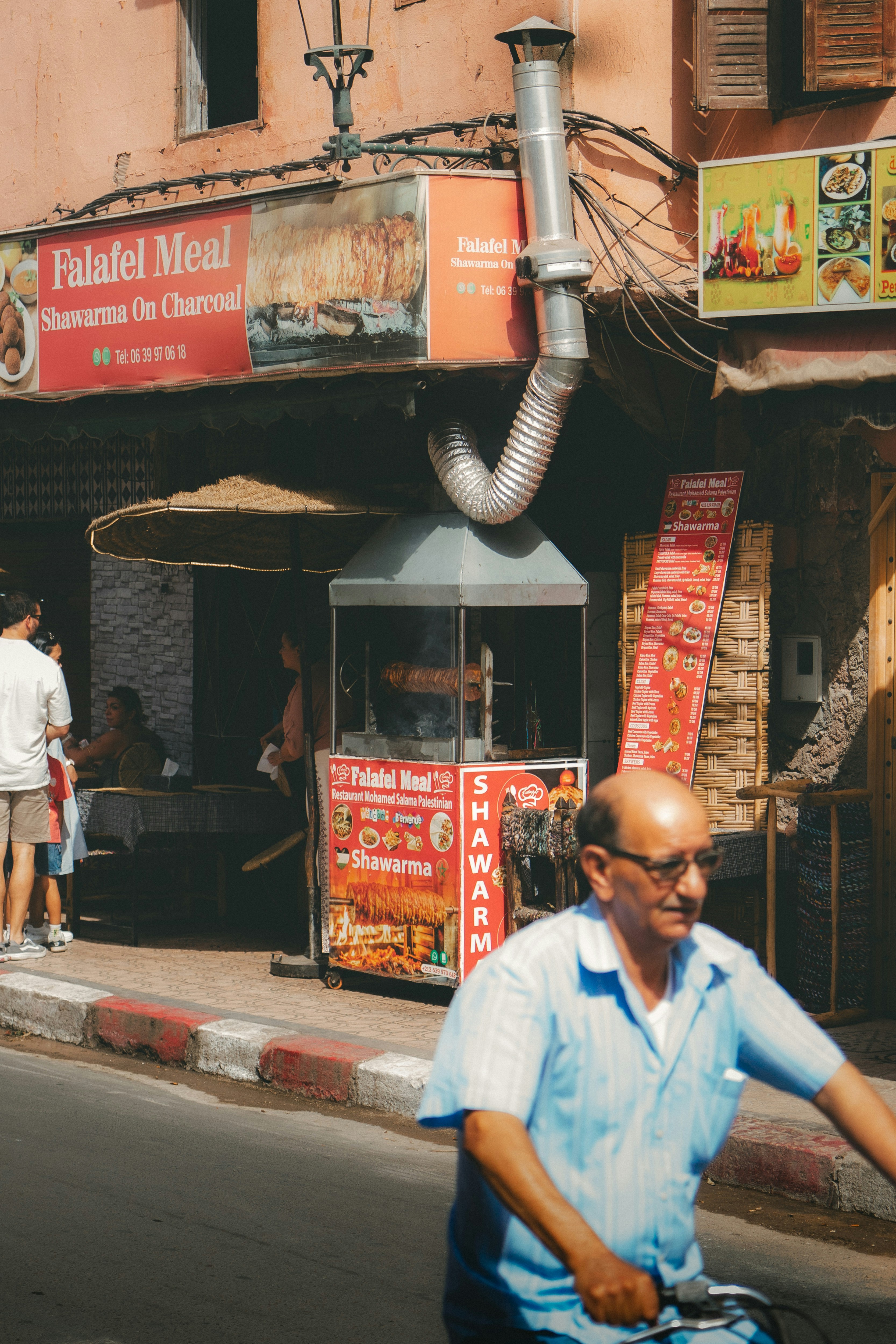 Charcoal Shawarma Lane: Ductwork, Red Signage, and a Moment in Motion