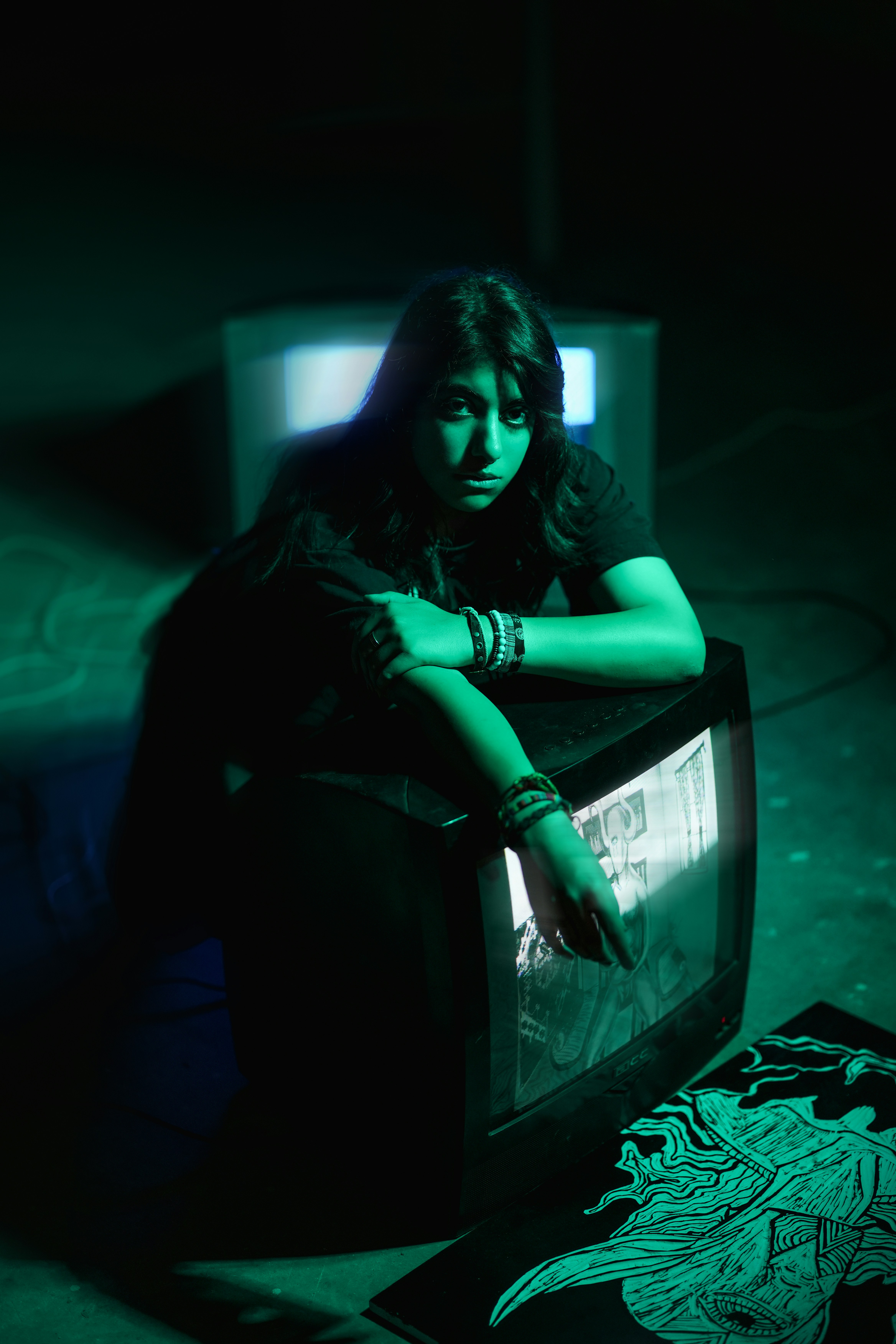 Woman posing with vintage televisions in green light