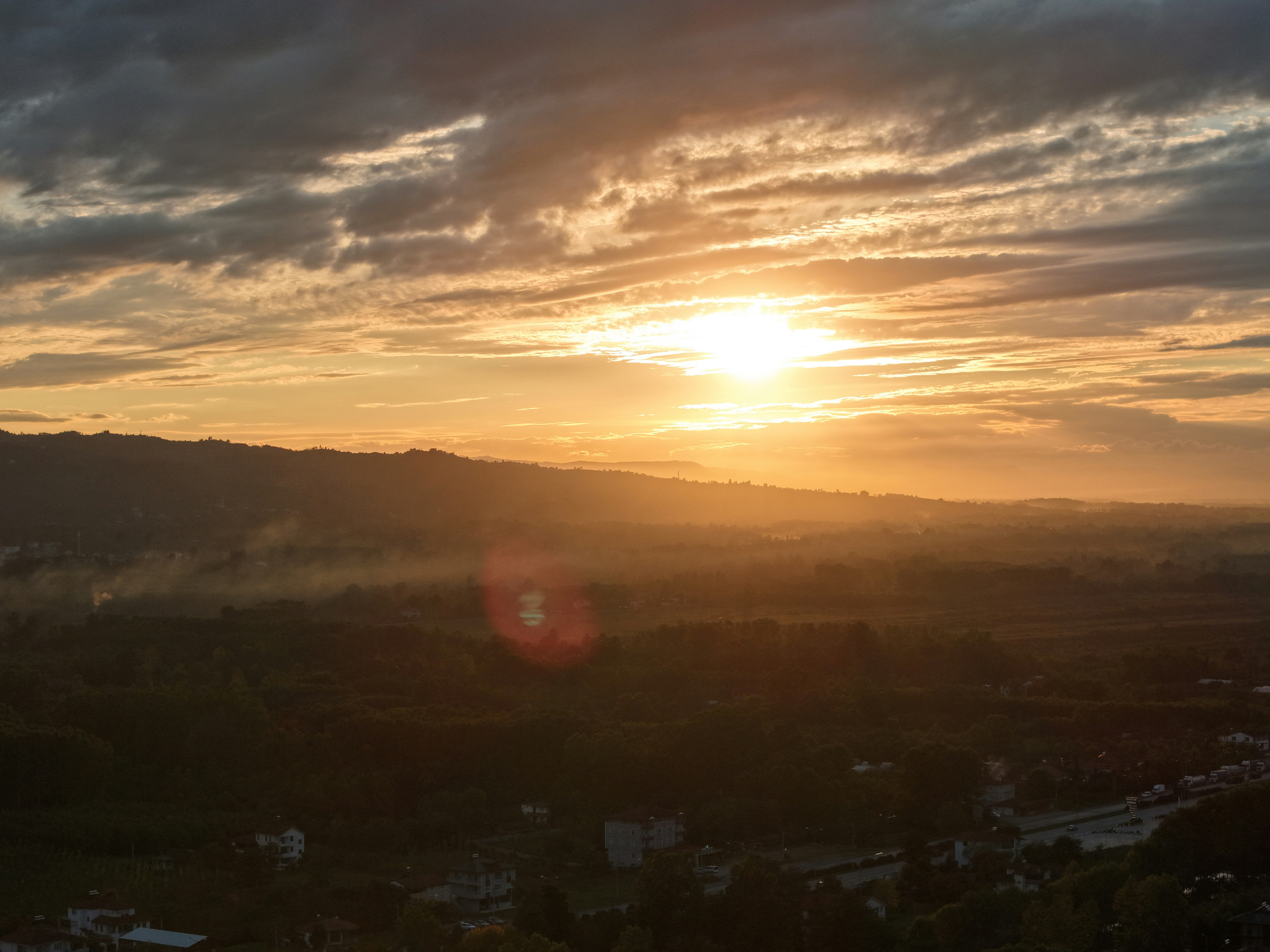 Sunrise over a misty, rolling landscape.
