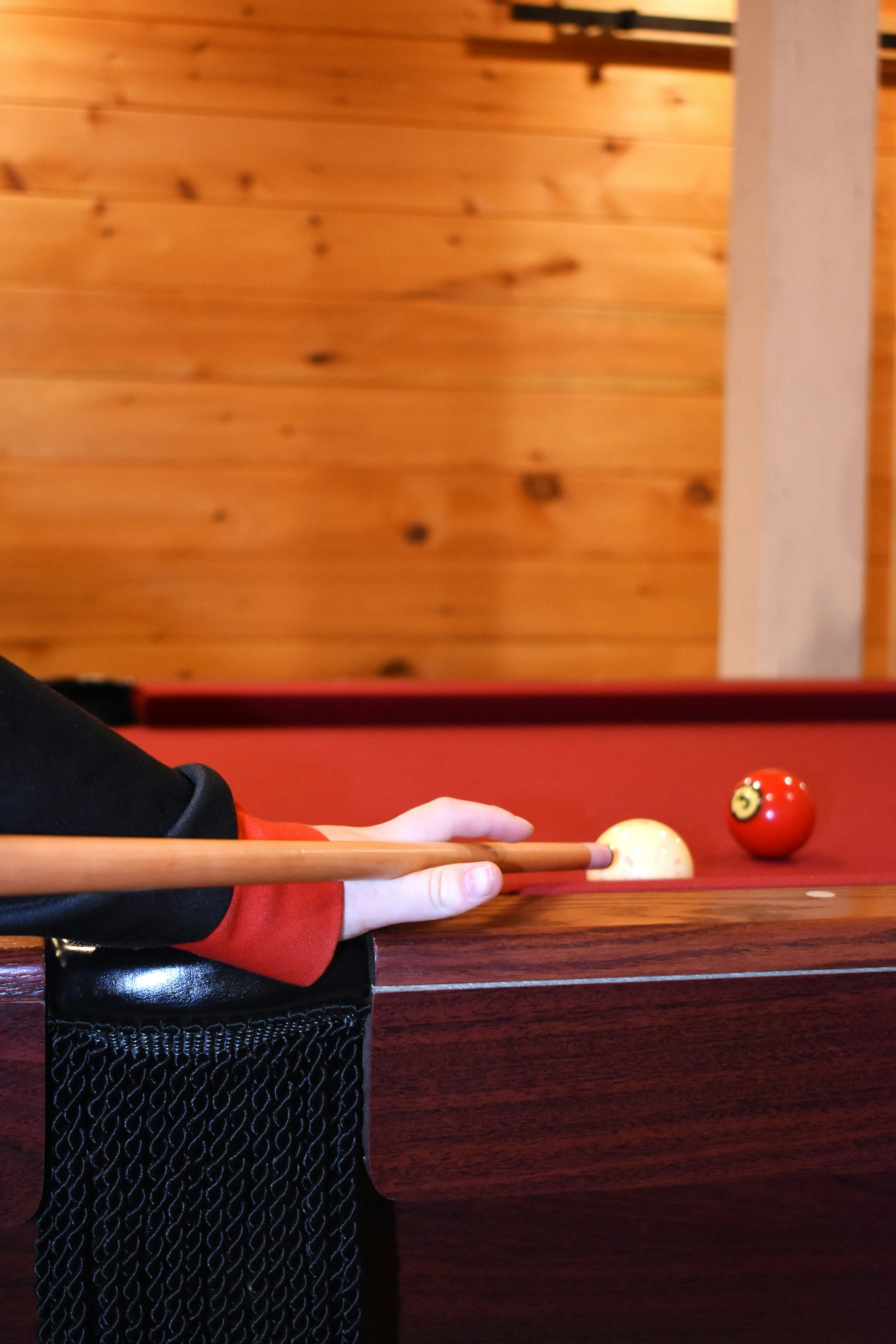 Person playing billiards with cue stick