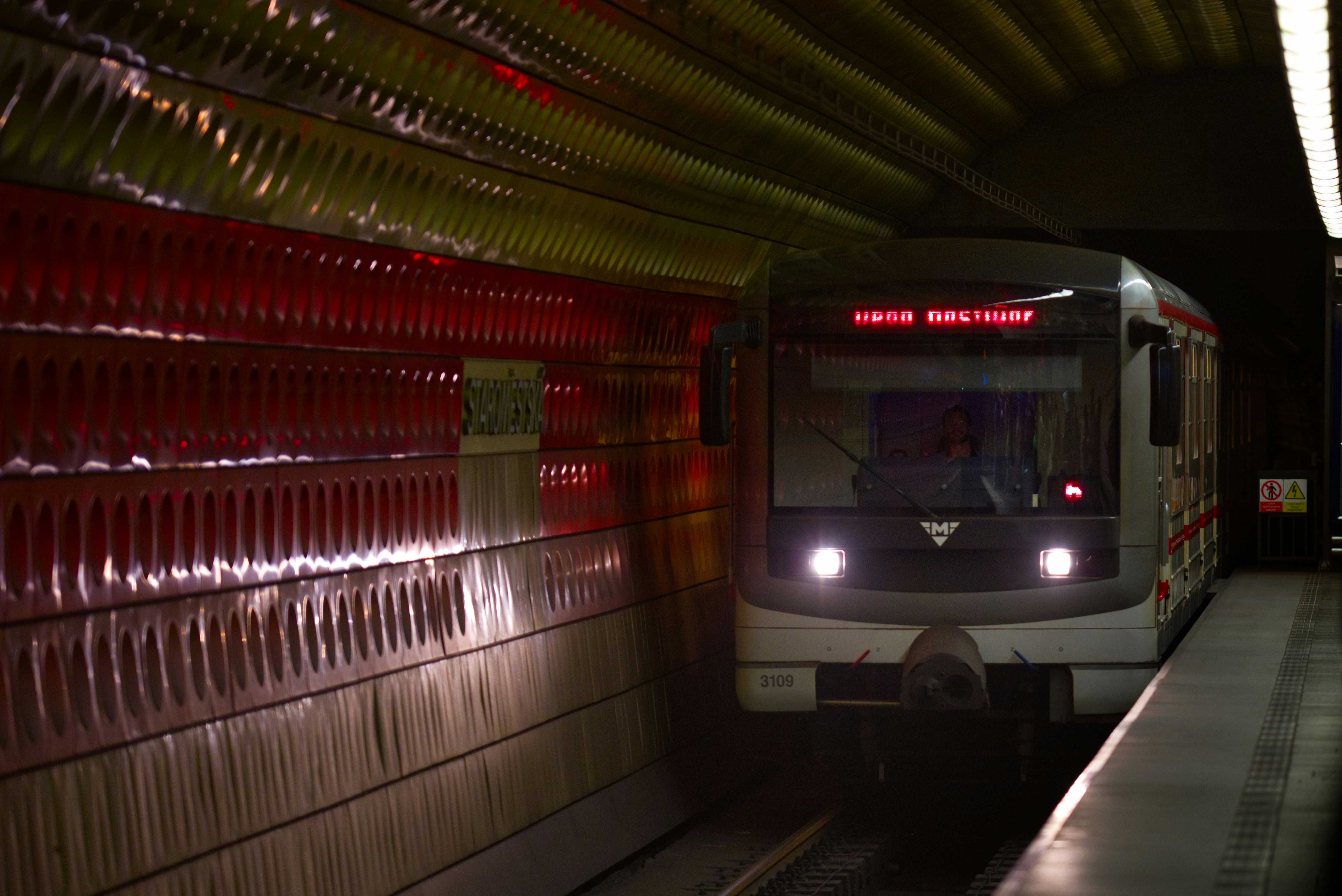 Red Corridor Approach: Front of a metro train gliding into a glow-lit tunnel