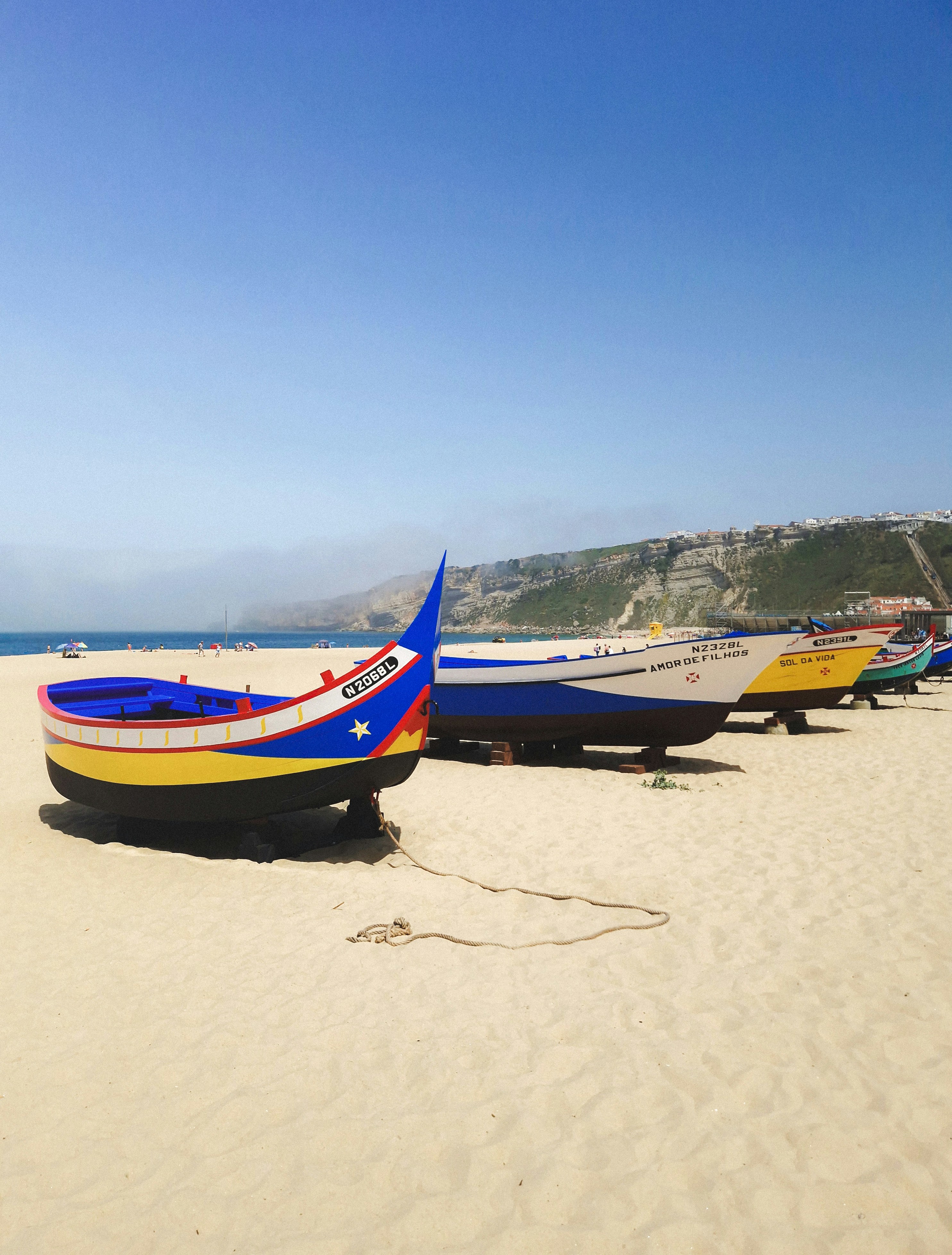 Colorful fishing boats resting on a sandy beach under a clear blue sky. The scene captures the essence of coastal life.