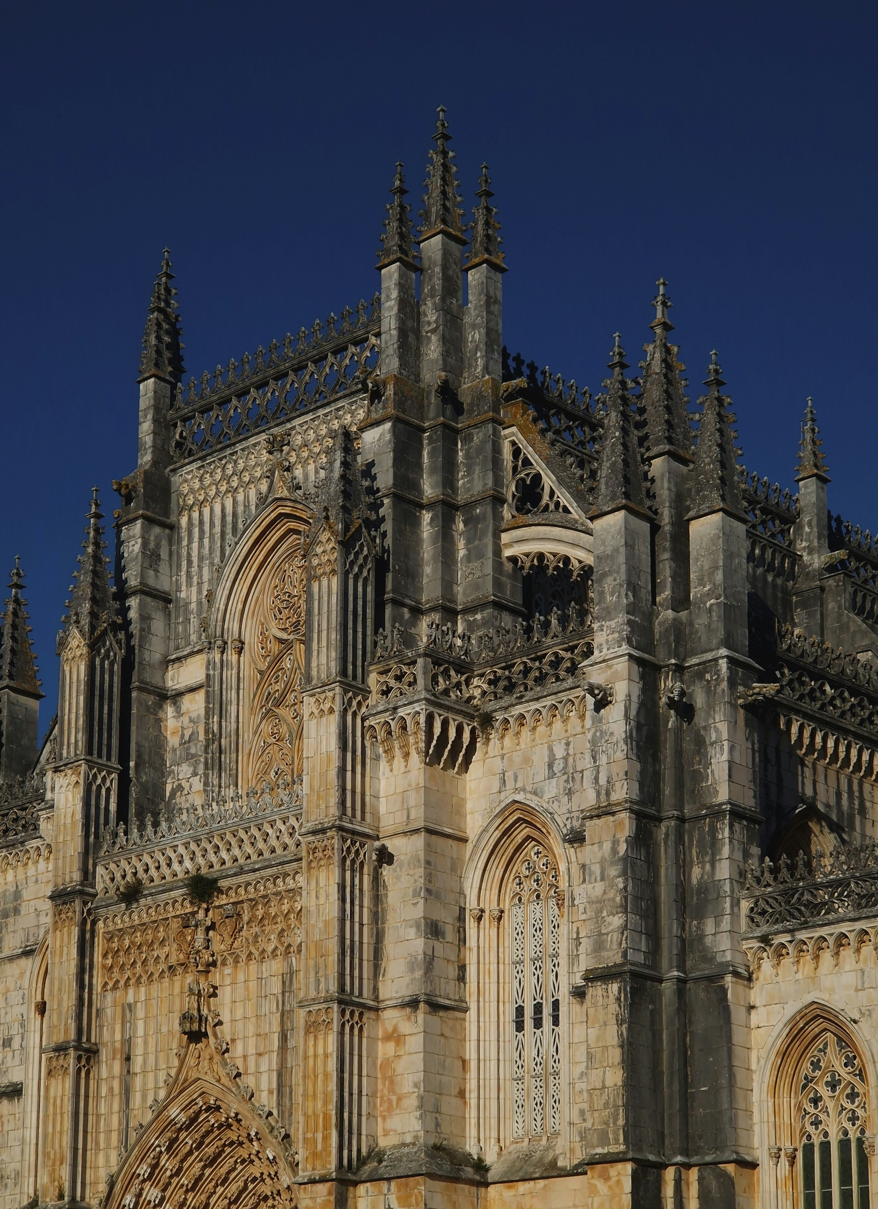 Elaborate Gothic architecture with pointed arches and intricate detailing, showcasing a historic cathedral against a clear blue sky.
