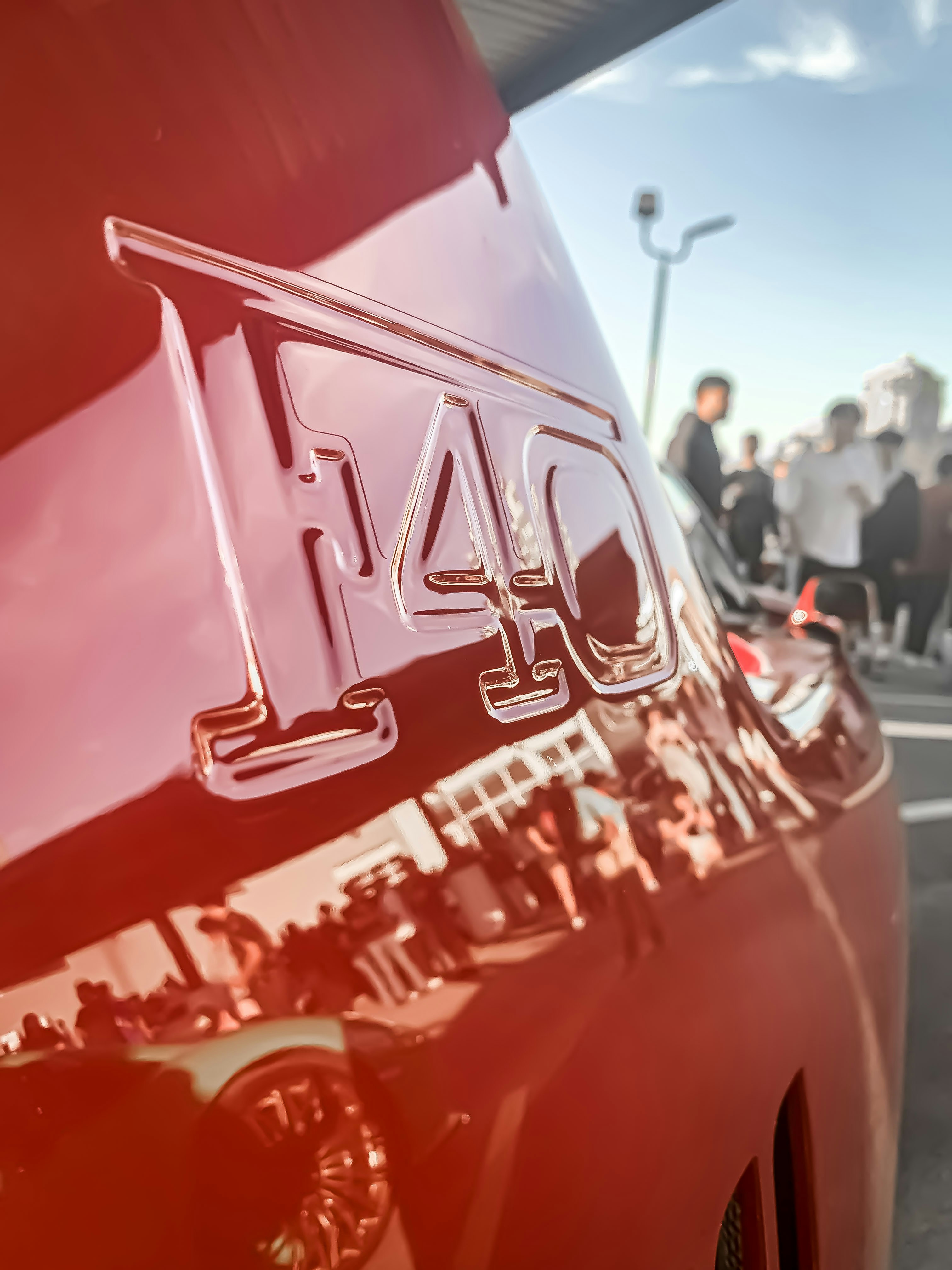Close-up of a red car badge with surrounding reflected scene