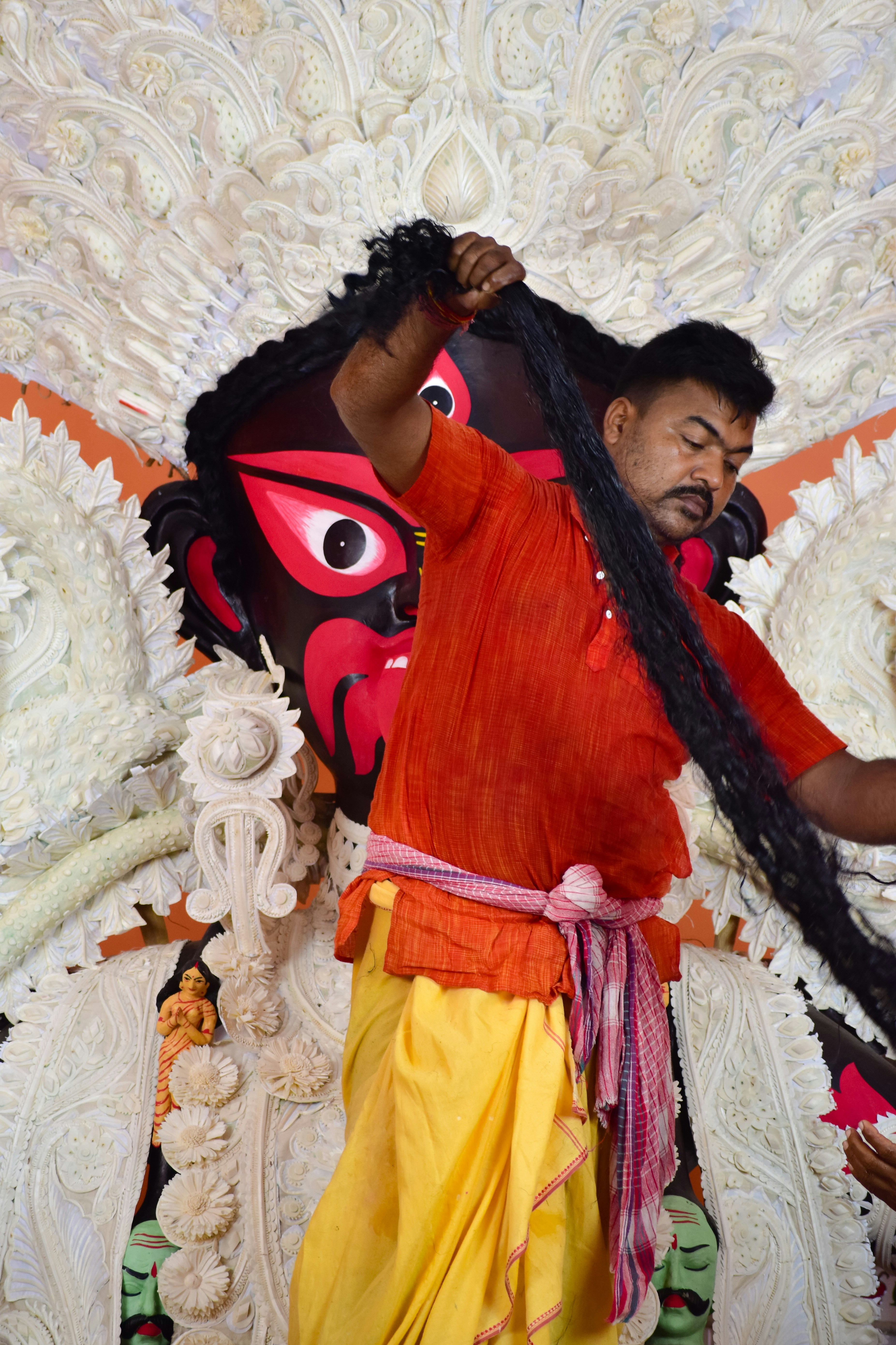 Orange-clad performer amid an ivory ceremonial backdrop