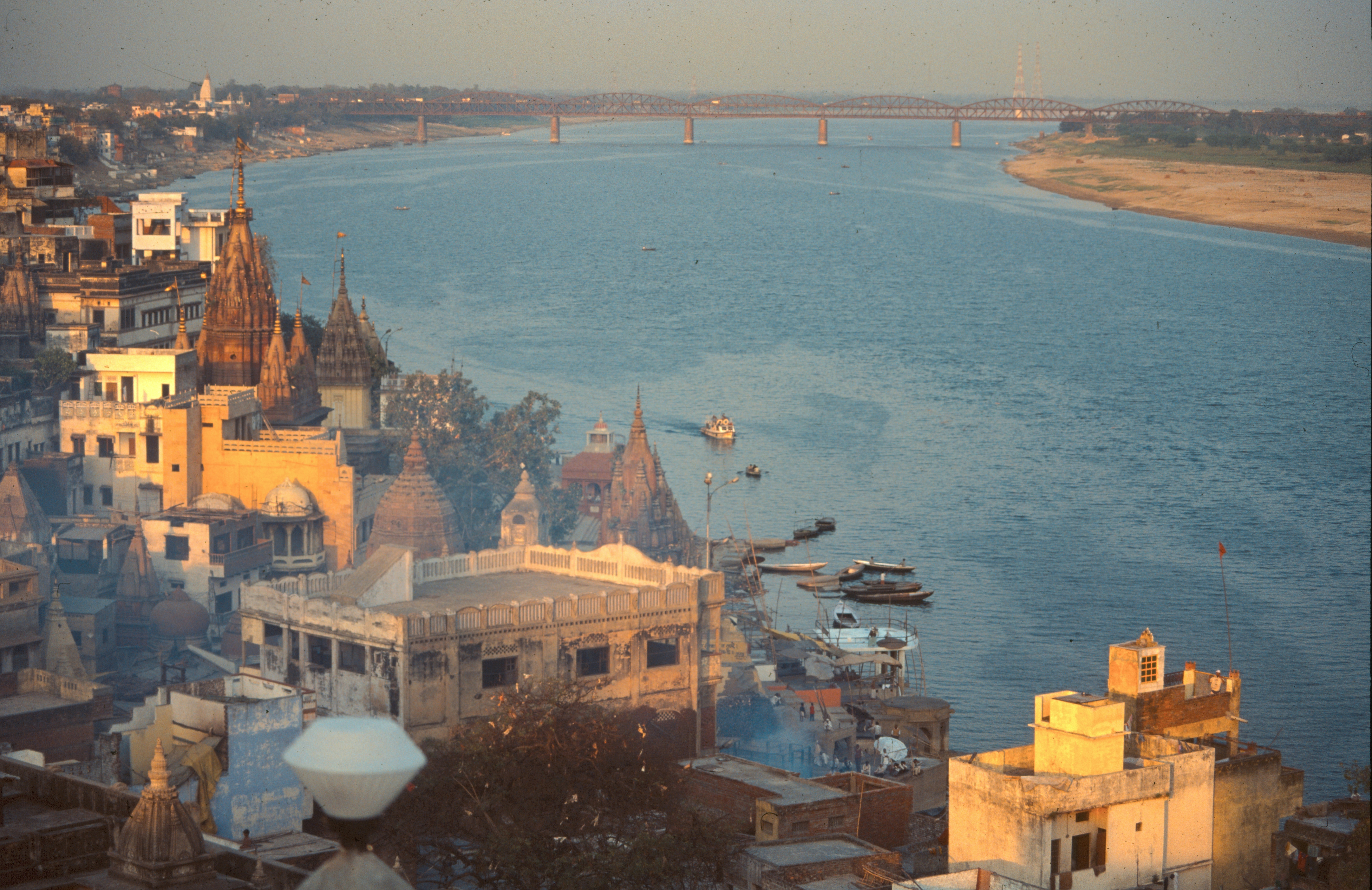 Ganges river with buildings and temples at sunset.