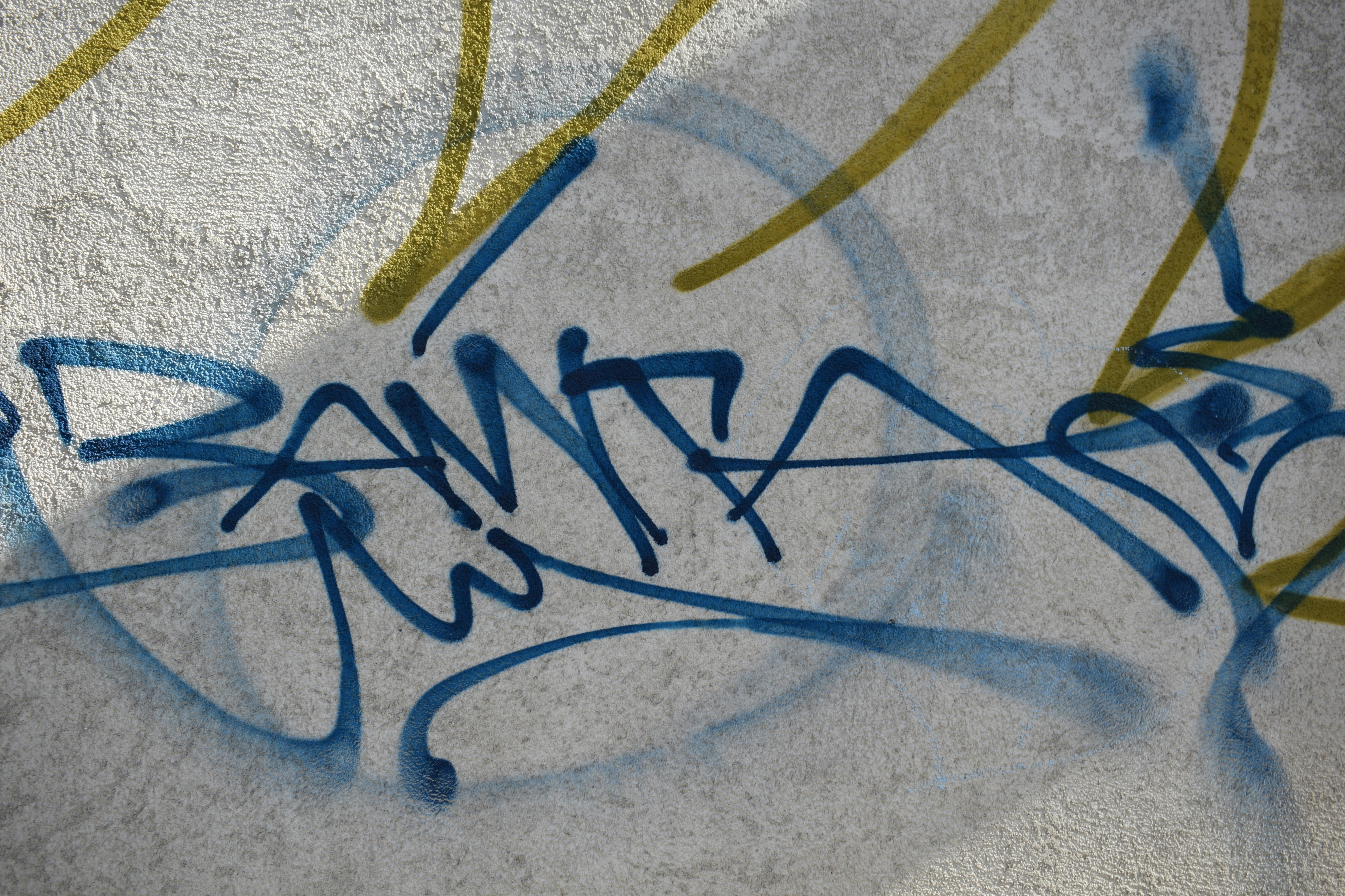 Vibrant blue graffiti art sprawled across a textured wall, showcasing intricate lettering and dynamic lines.