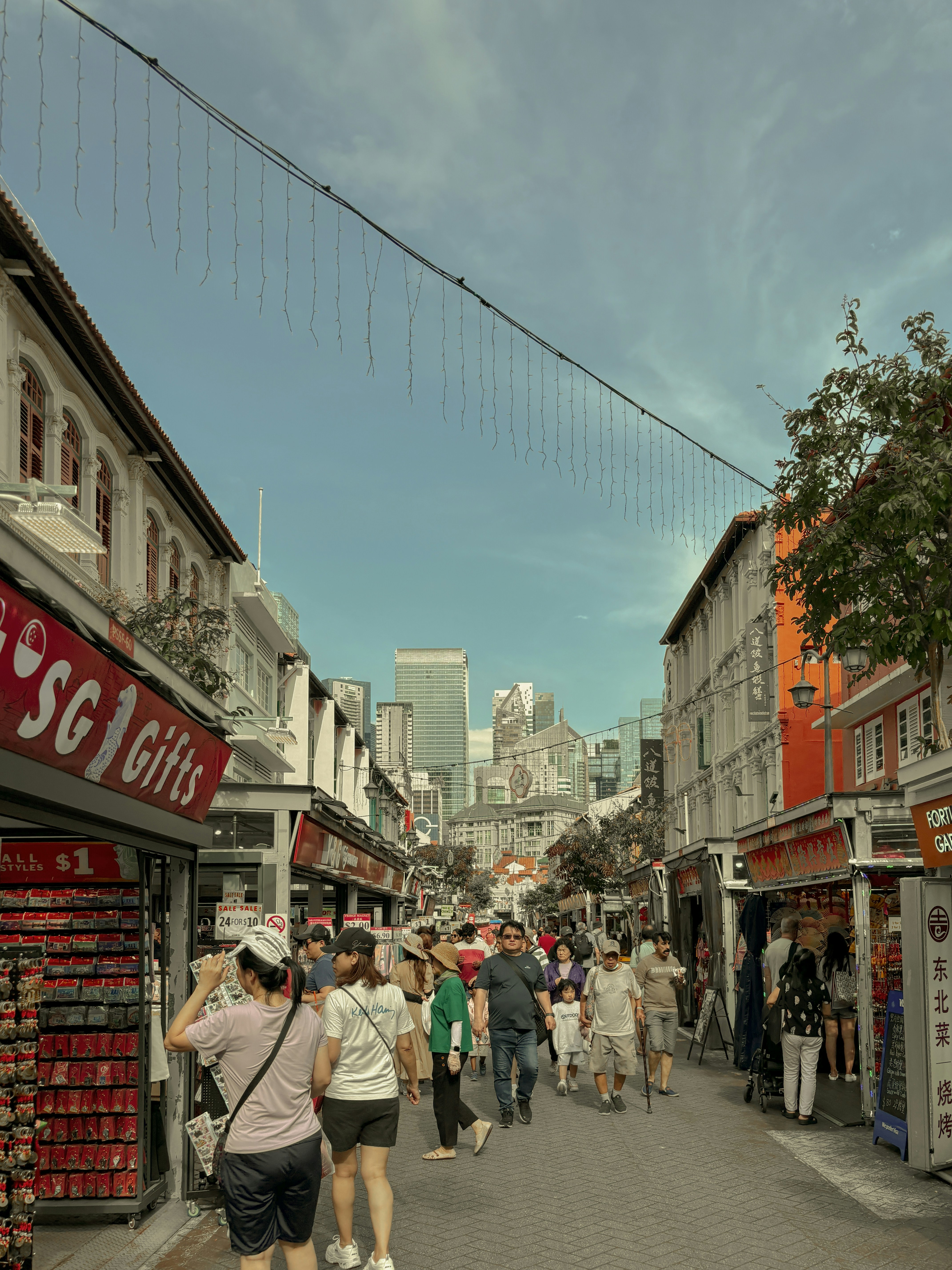 Bustling street scene in a vibrant urban market, showcasing shops and diverse crowds amidst modern architecture in the background.
