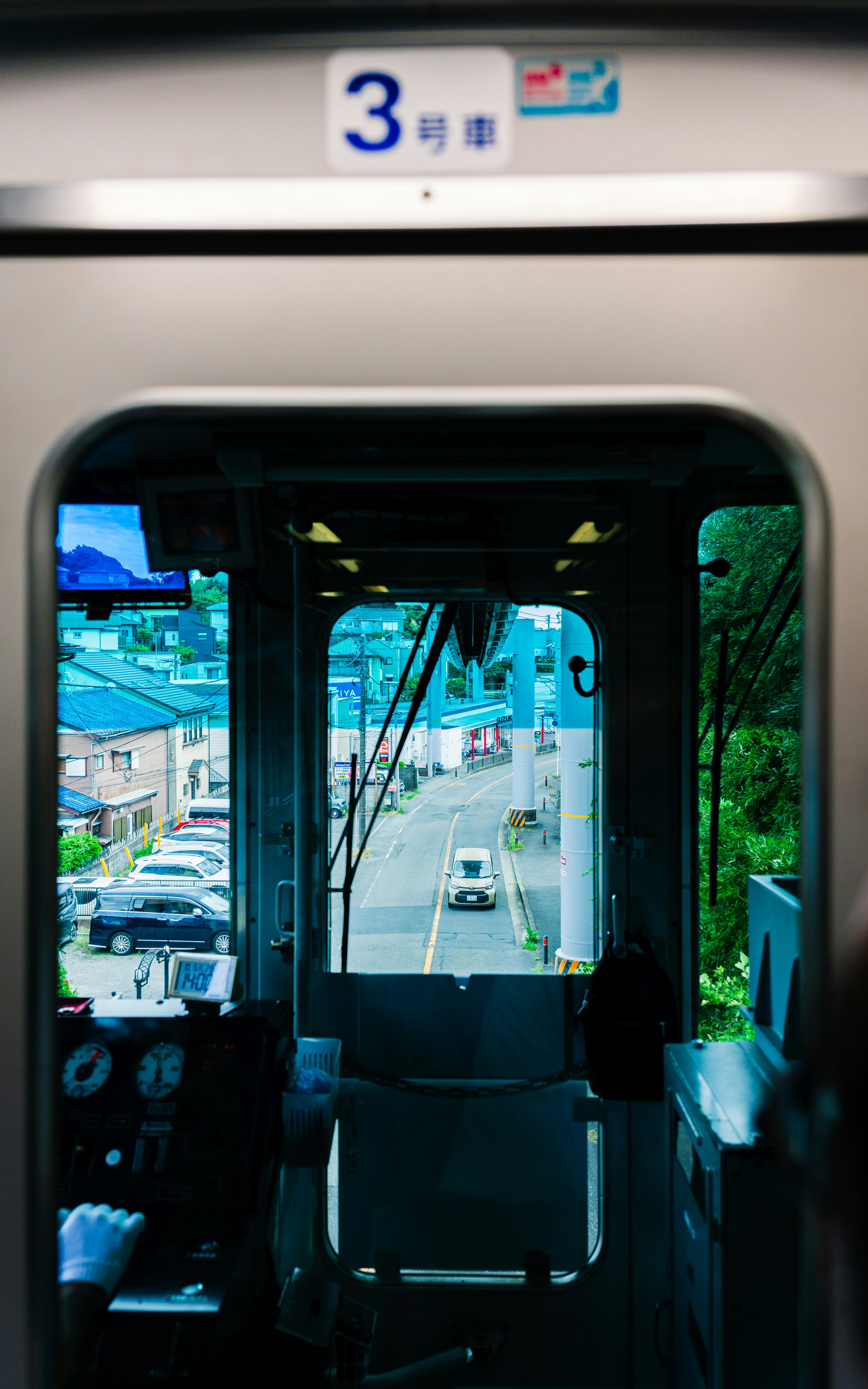View from inside a train cabin, showcasing the road and buildings outside. The perspective highlights the interaction between the vehicle and its urban surroundings.