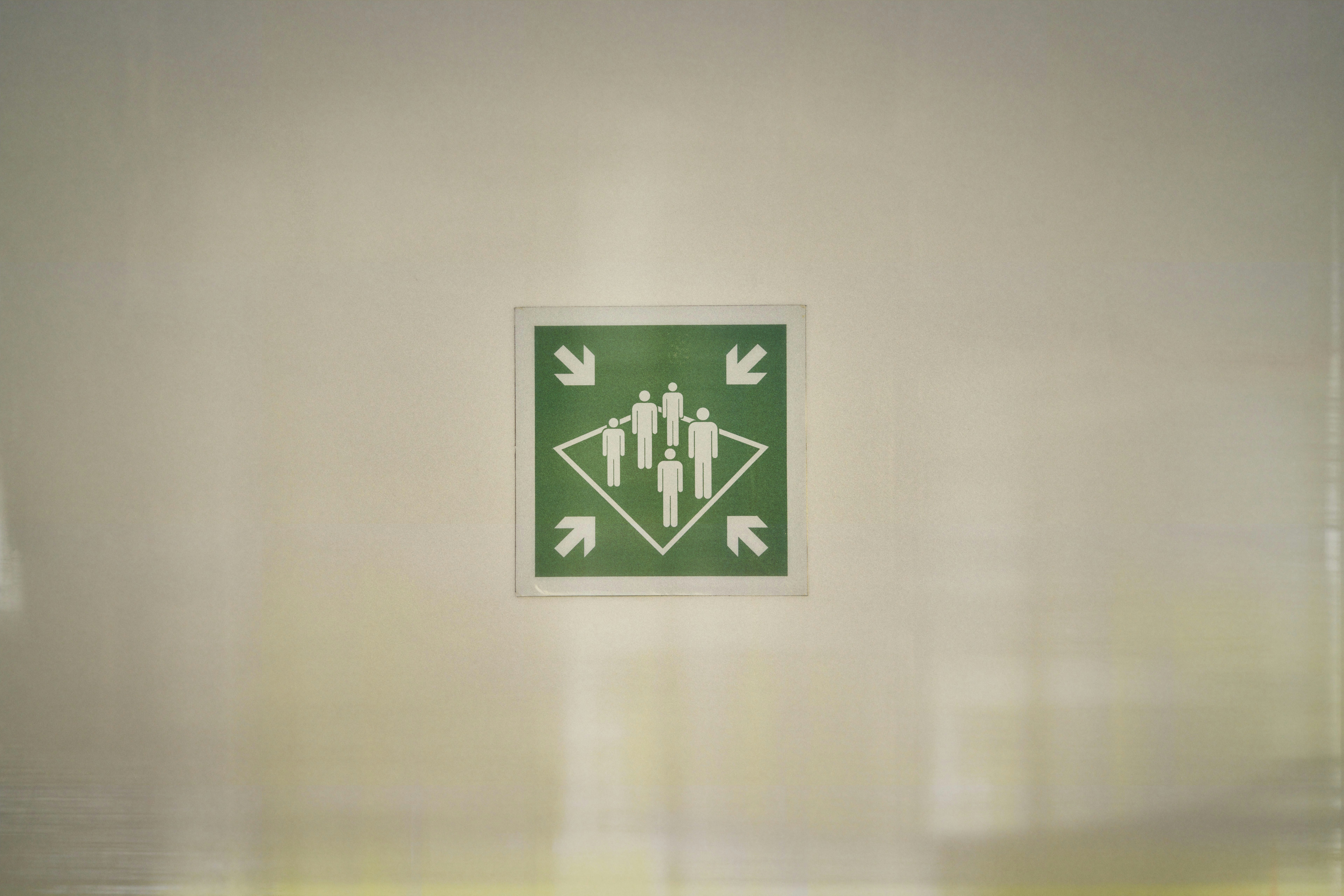 Green sign with people and arrows indicating assembly point