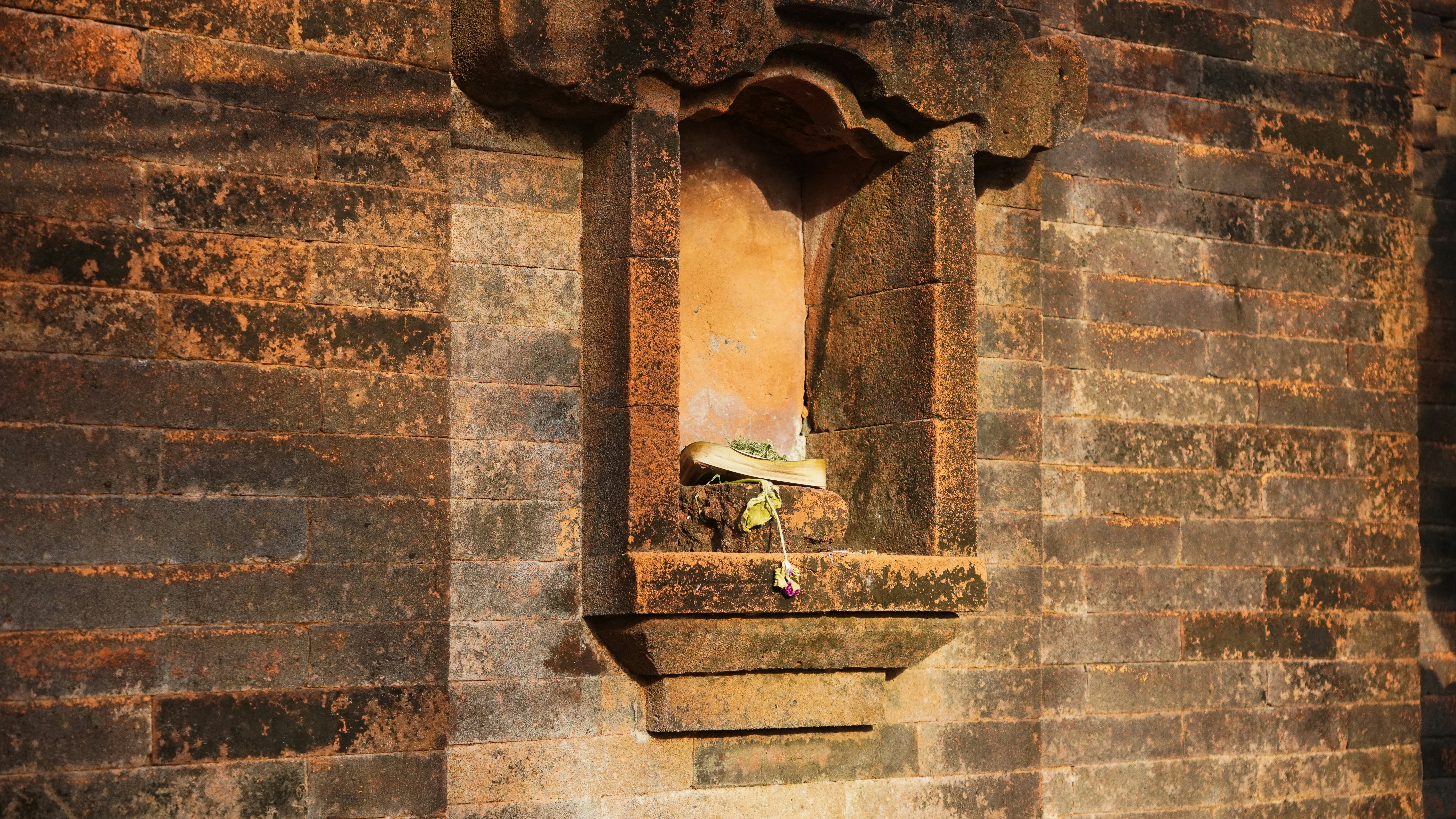Sunlit Niche: A Tiny Shrine Nestled in Weathered Brick