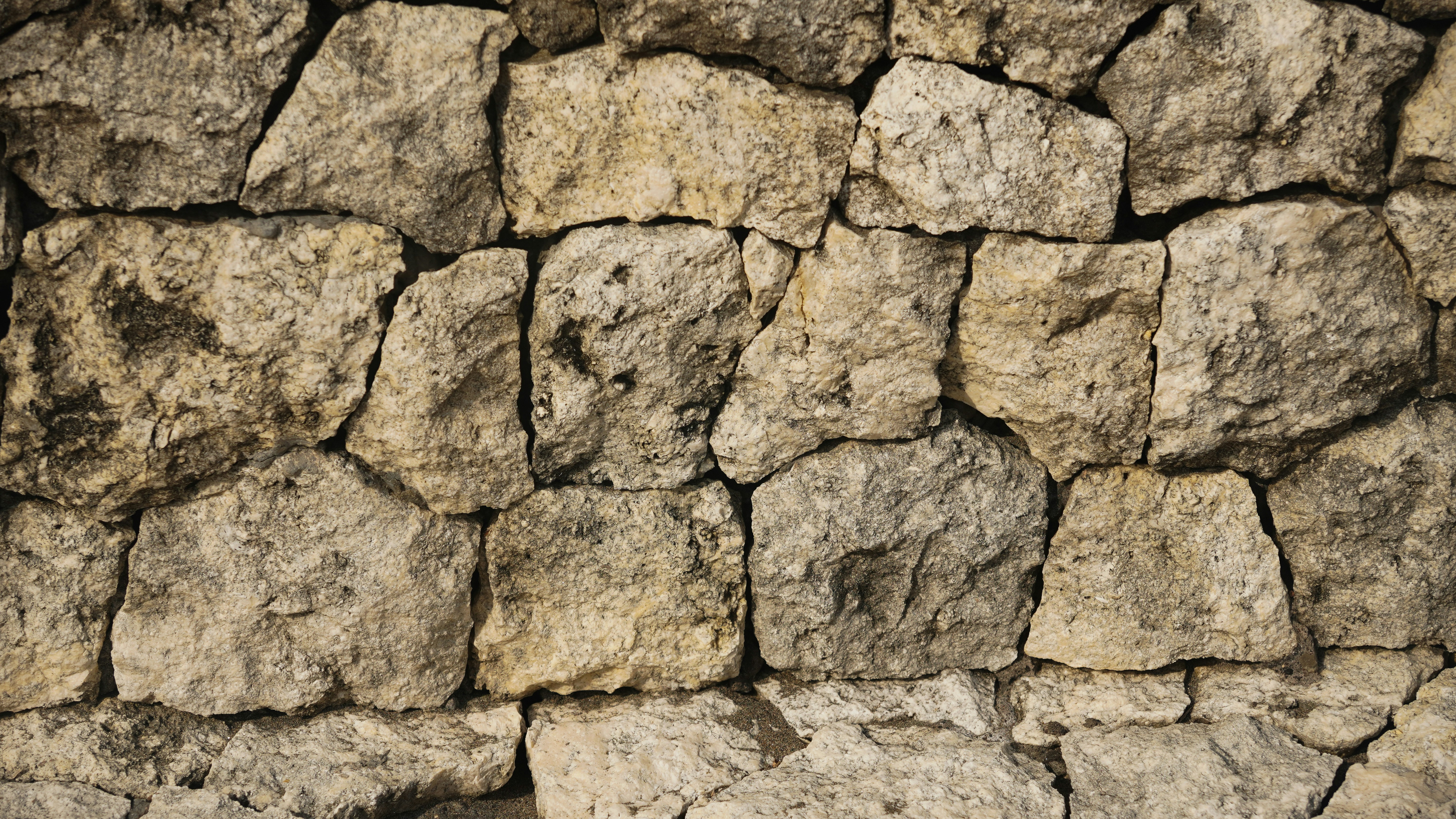 A textured stone wall with rough, irregular blocks.