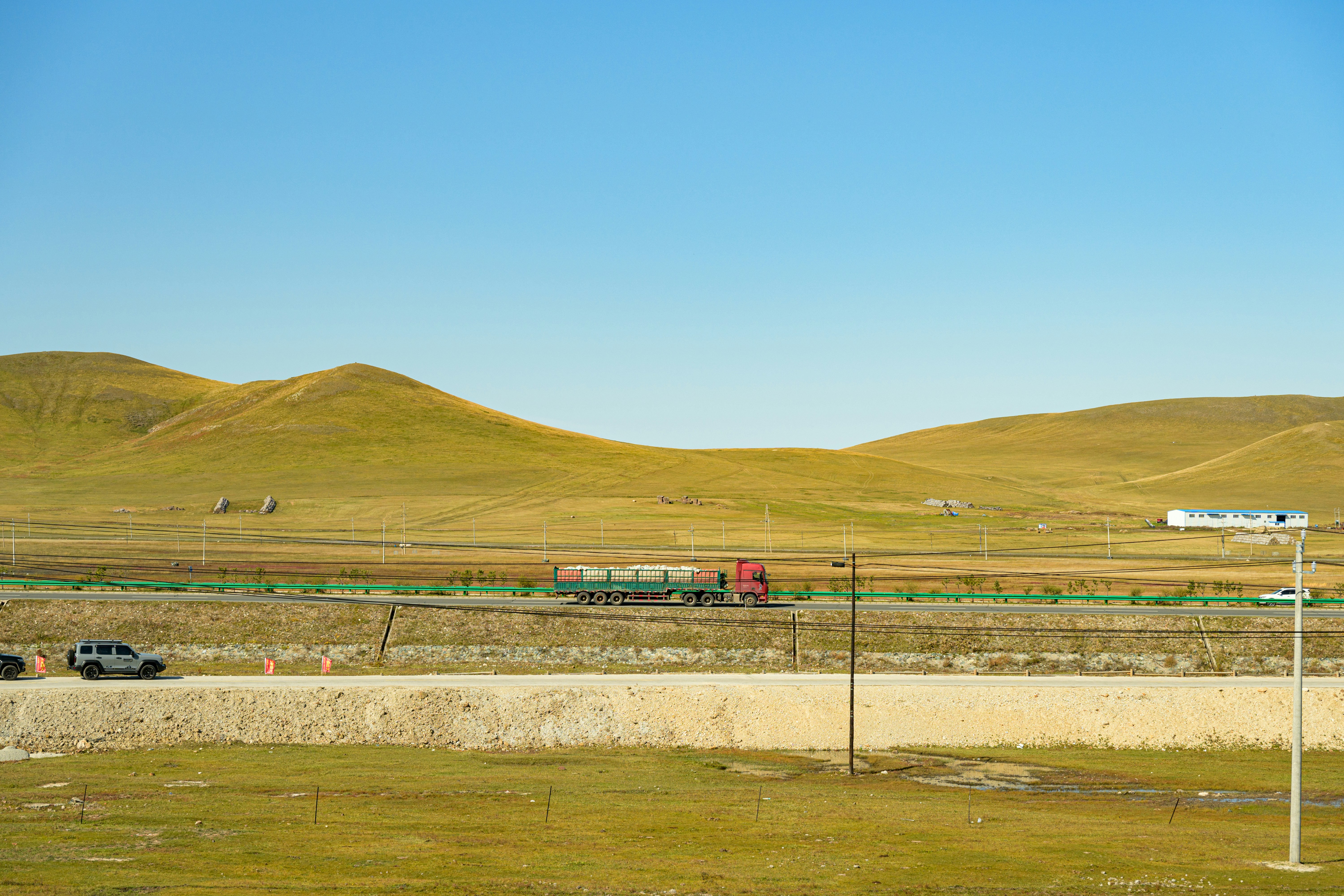 Red tractor working in a field with rolling hills.