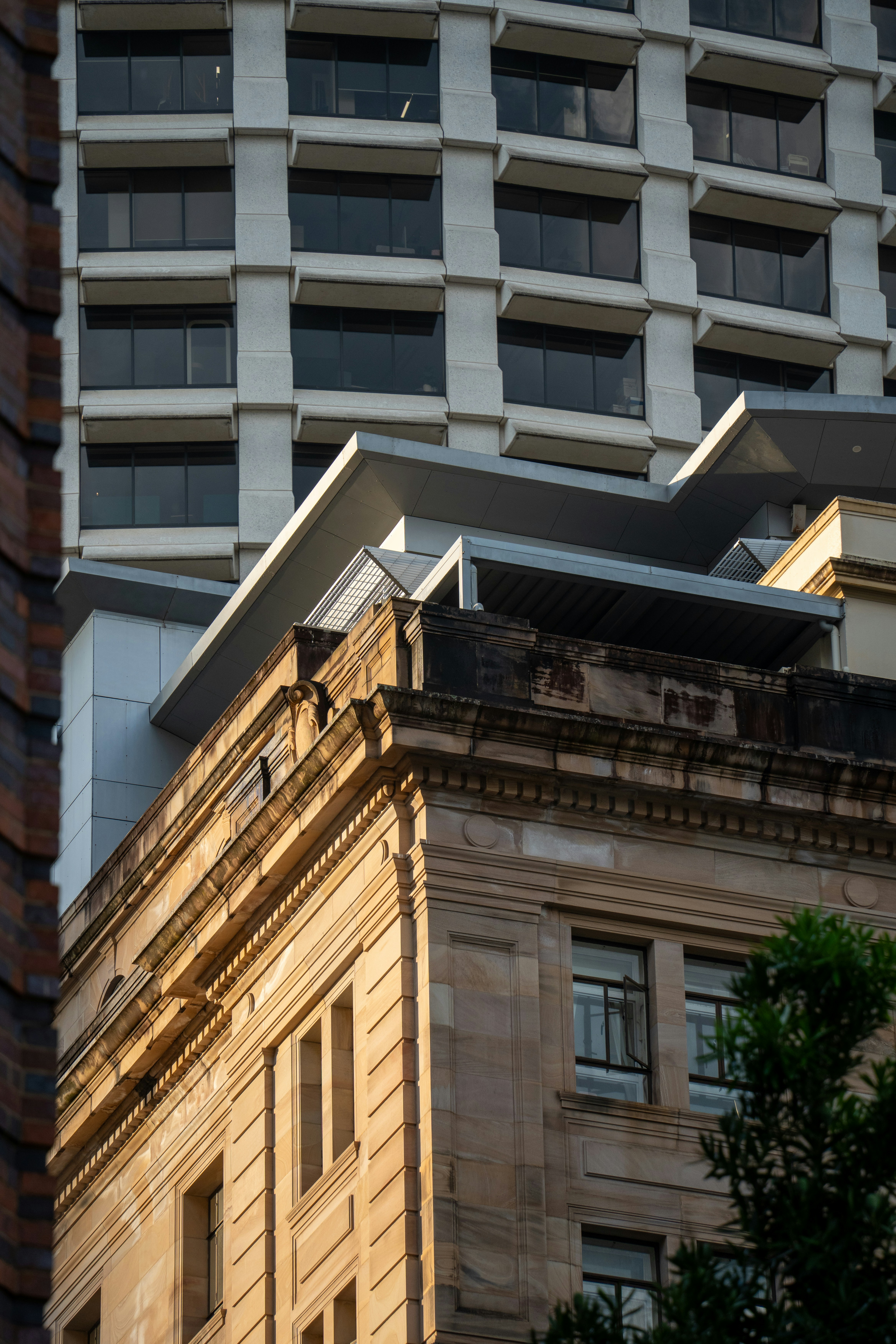A juxtaposition of a classic sandstone building and a sleek modern structure, showcasing urban architectural diversity.