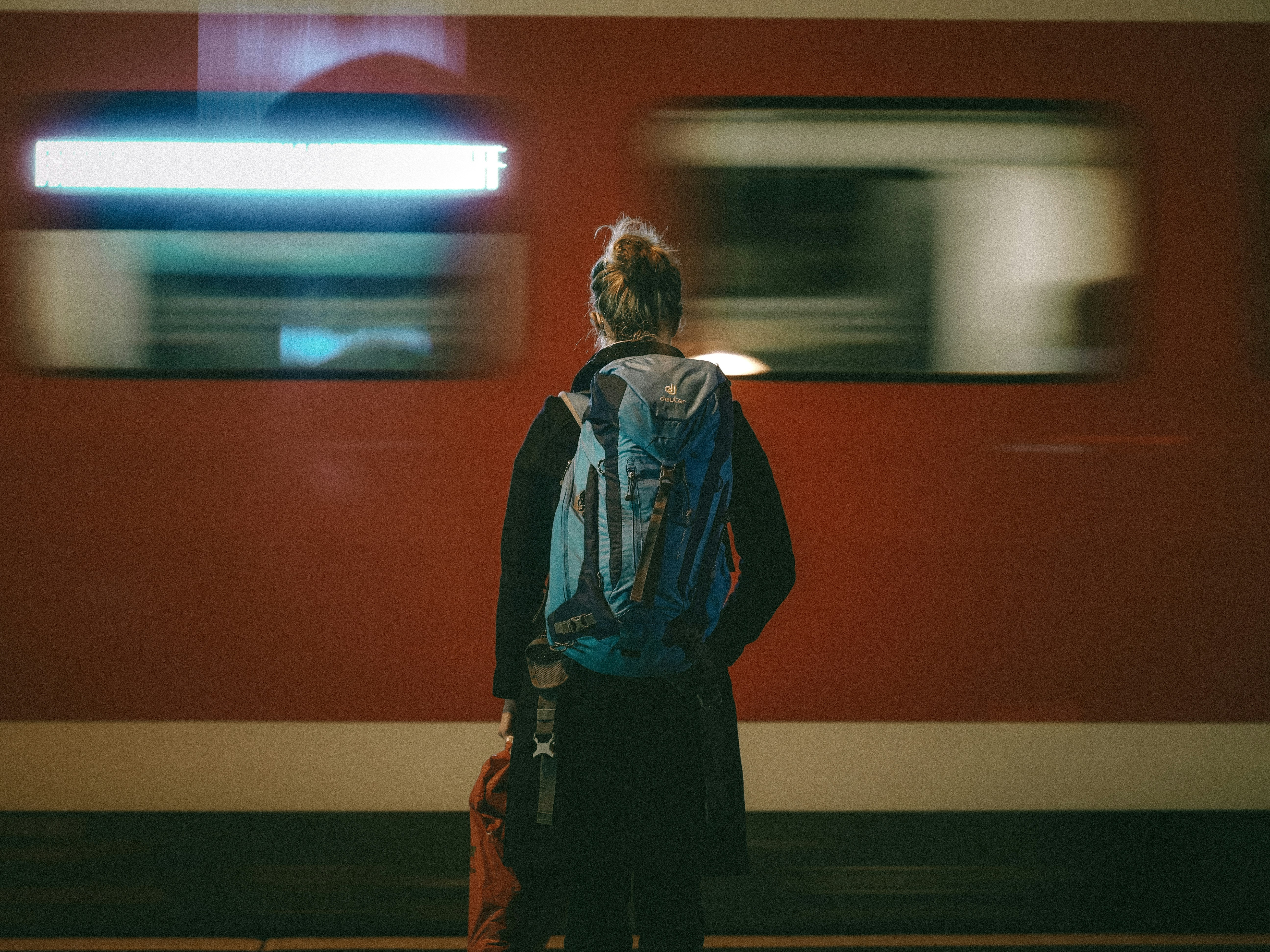 Woman with backpack watches a train pass by