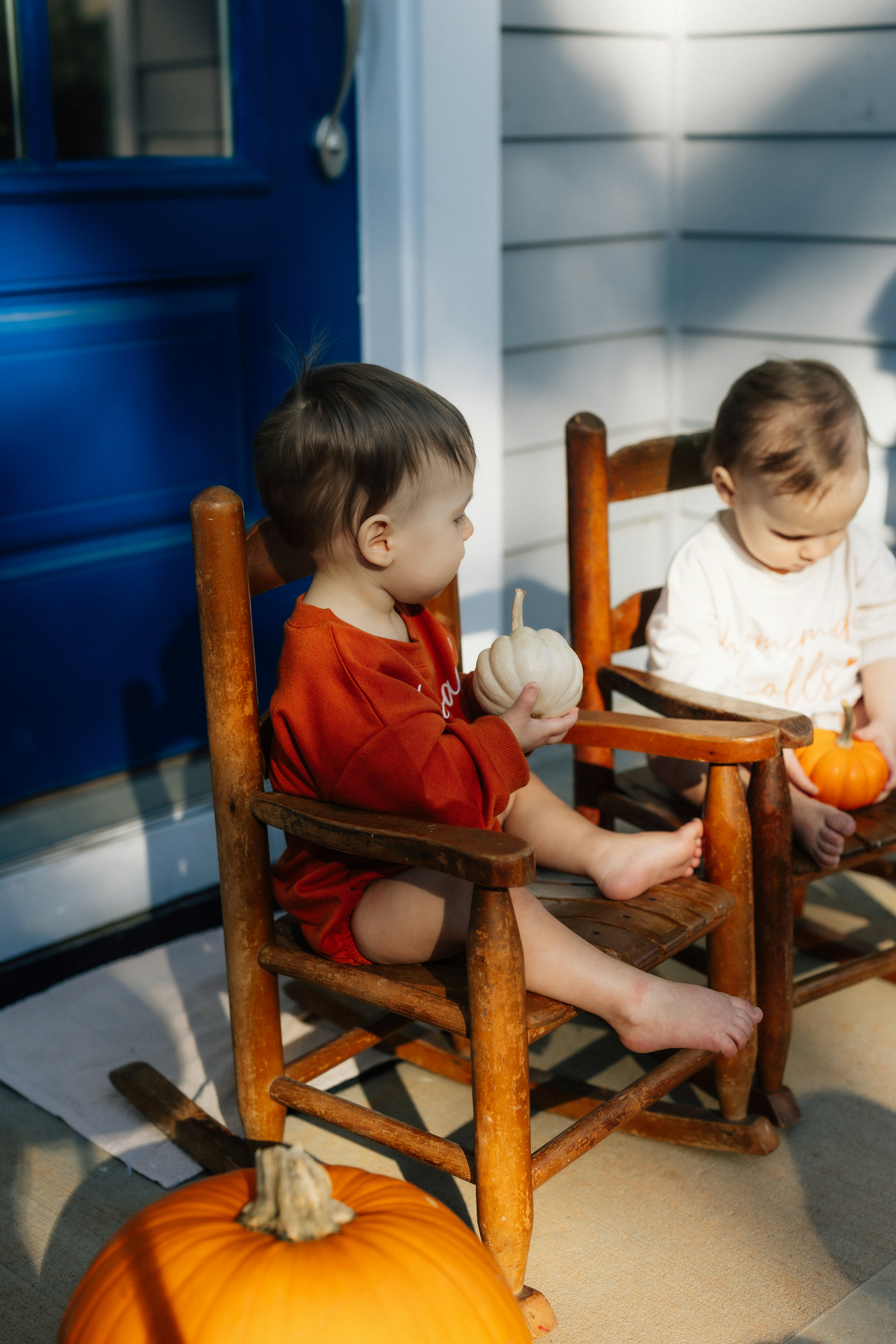 Autumn Porch Pause: A Toddler Sits with a Pumpkin in Soft Morning Light