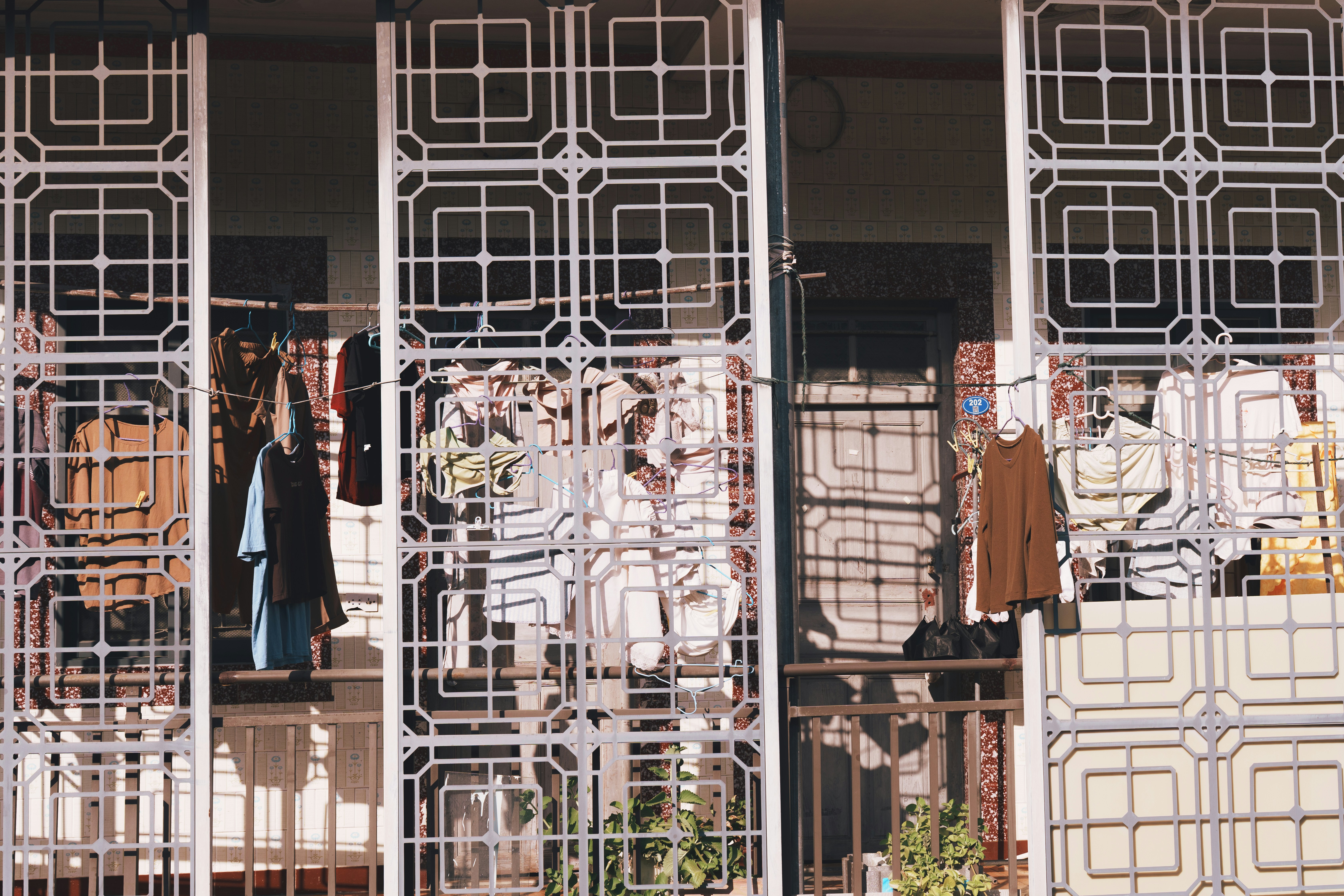 Clothes drying on a balcony behind decorative screens.