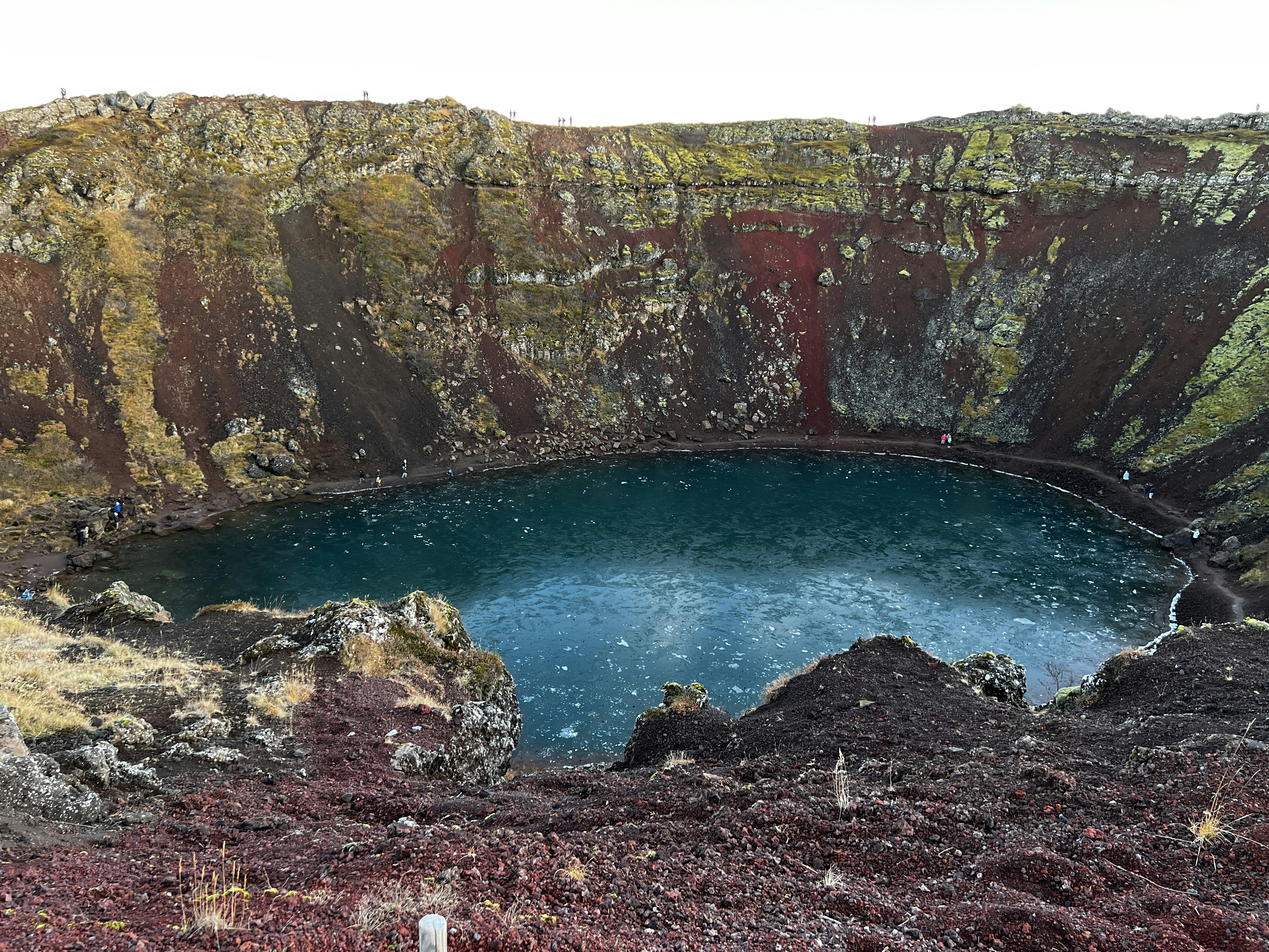Kerið Crater's serene pool, surrounded by the rugged beauty of Iceland's Grímsnes region. | Volcanic crater lake with colorful rocky rim