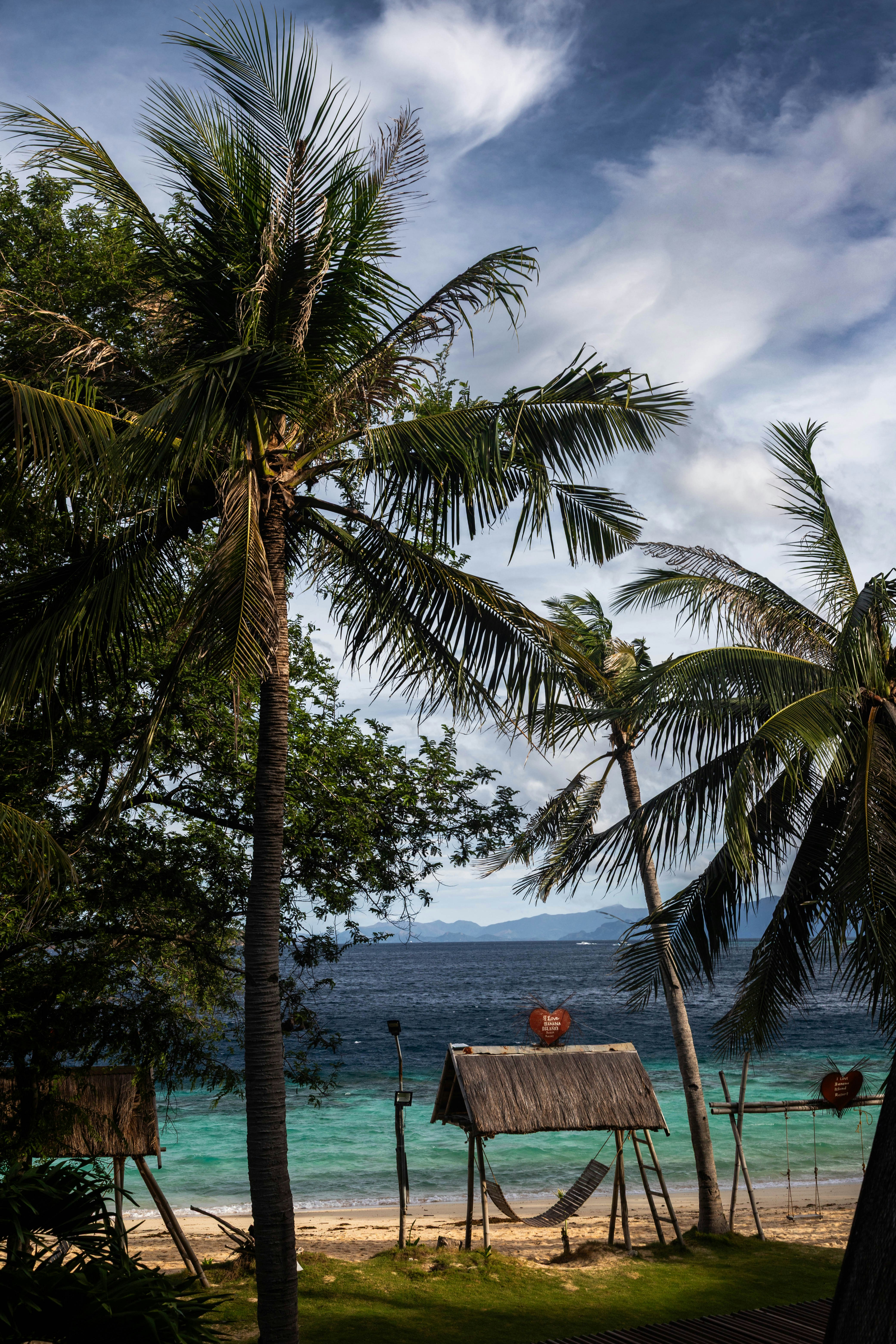 Thatched Shelters and Turquoise Waves Framed by Palm Fronds