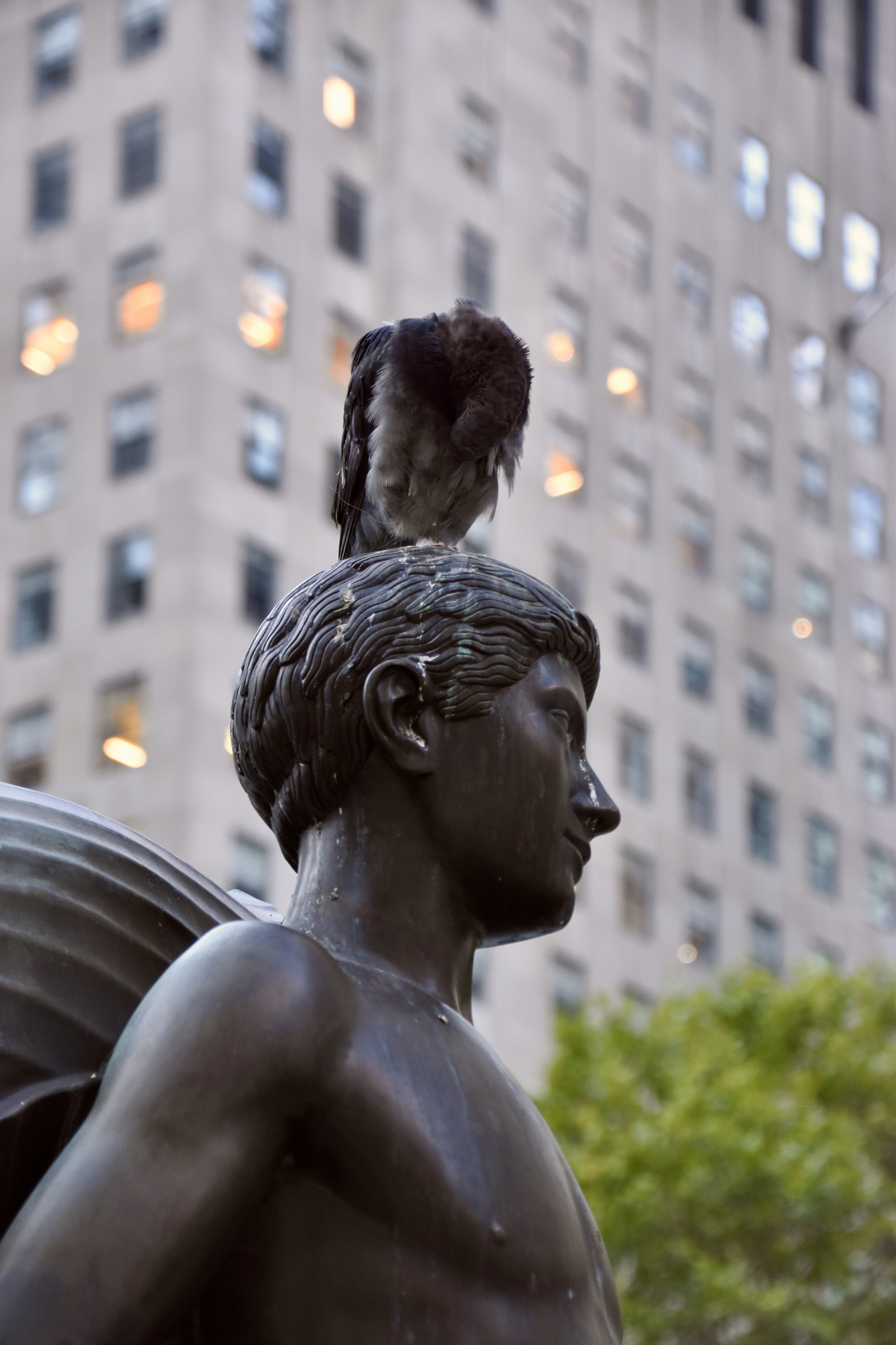 Perched Witness: Sparrow on a Bronze Head Among City Skyscrapers