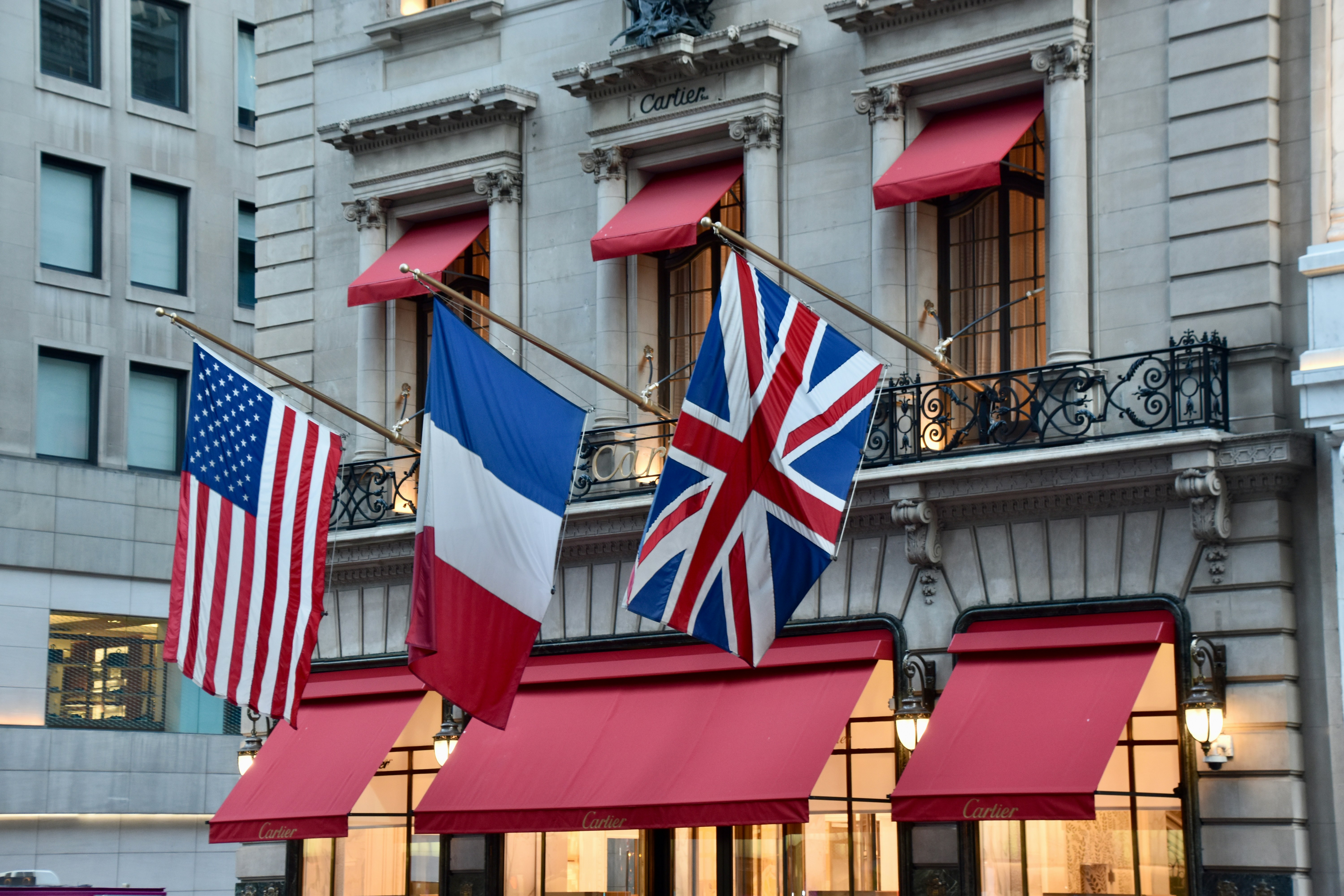 Flags of the United States, France, and the United Kingdom adorn the facade of a luxury boutique, highlighting international presence and sophistication.