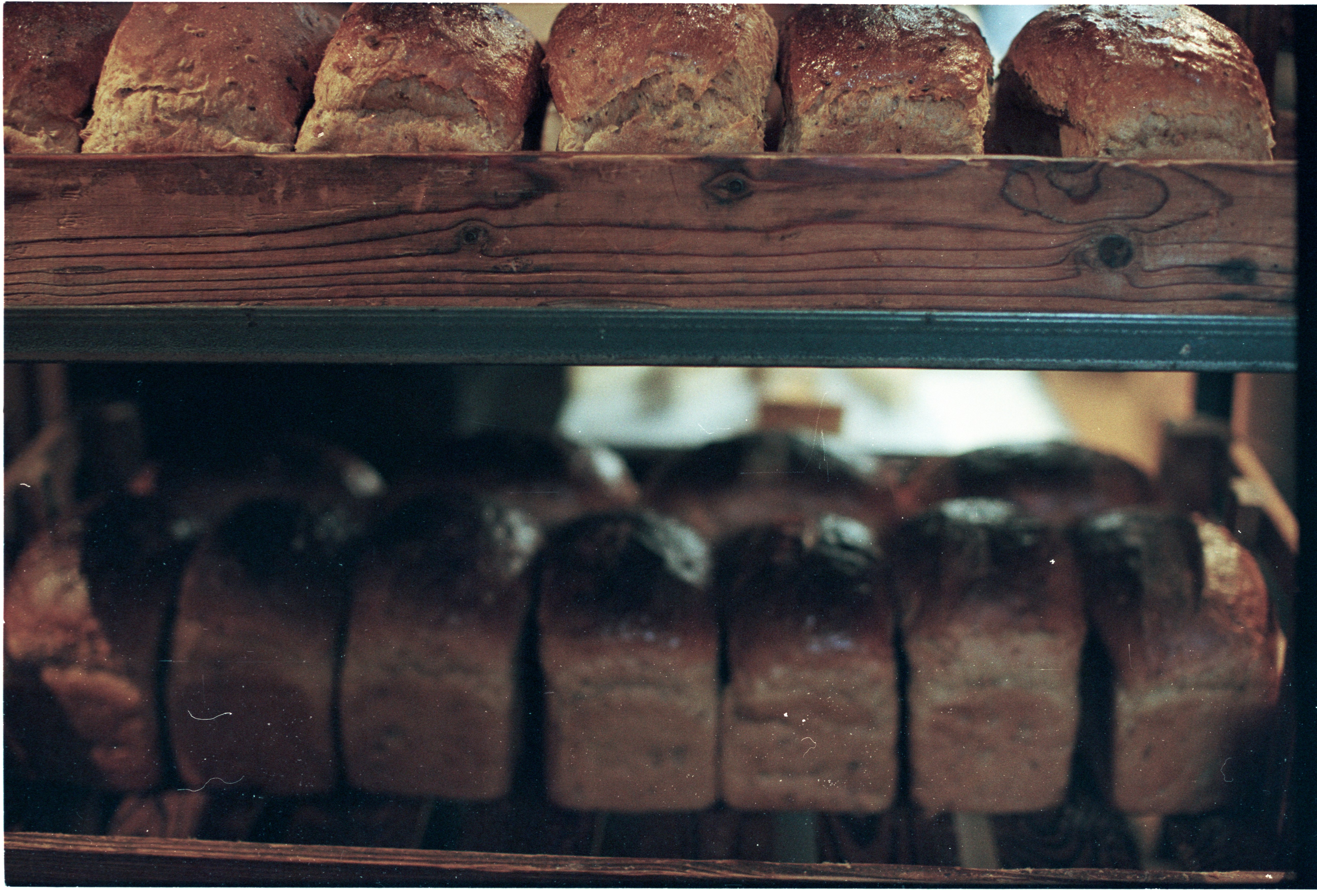 Freshly baked loaves of bread arranged on wooden shelves, showcasing their golden crusts and inviting texture.