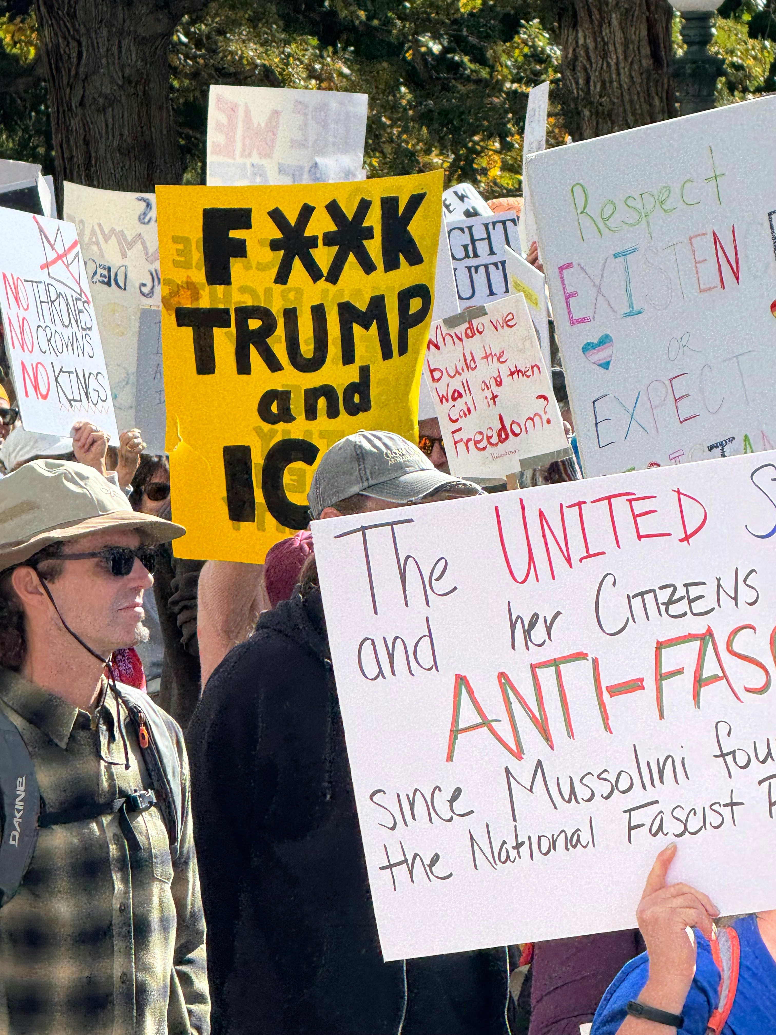 Protesters gather, holding signs expressing strong political sentiments, highlighting issues of freedom and anti-fascism.