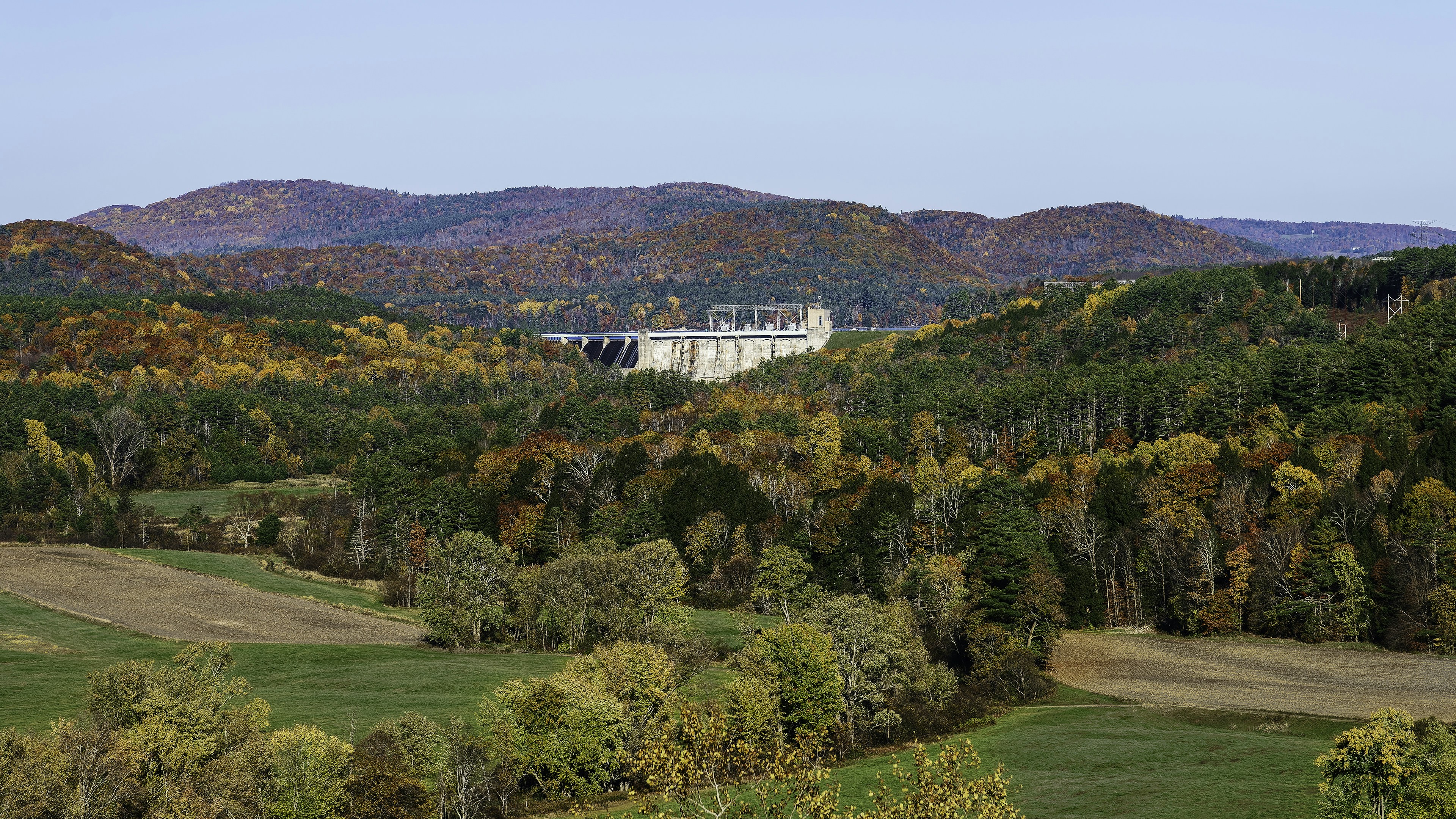 A hydroelectric dam nestled among vibrant autumn foliage, showcasing the interplay between natural landscapes and human ingenuity.