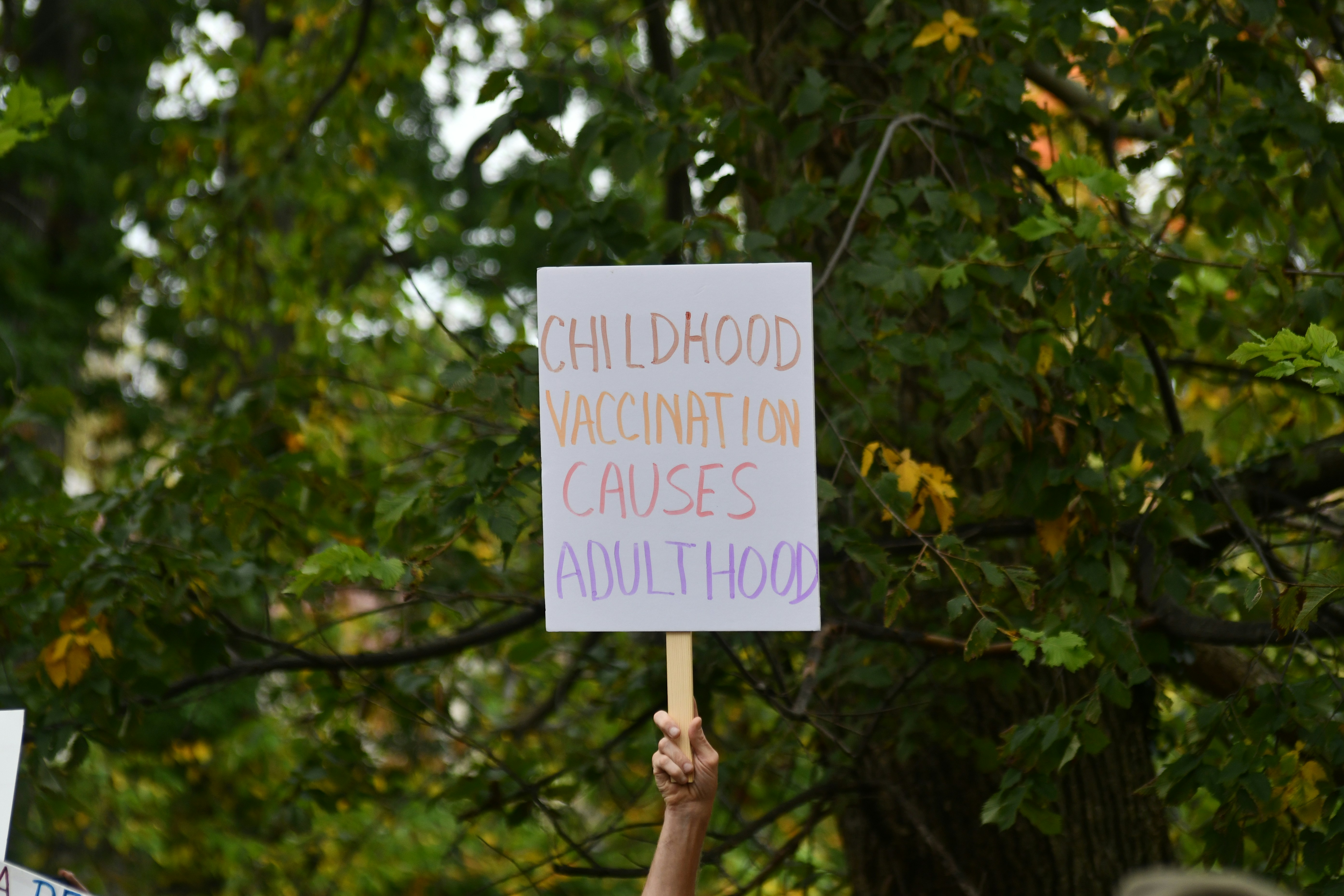 Sign reads: childhood vaccination causes adulthood.