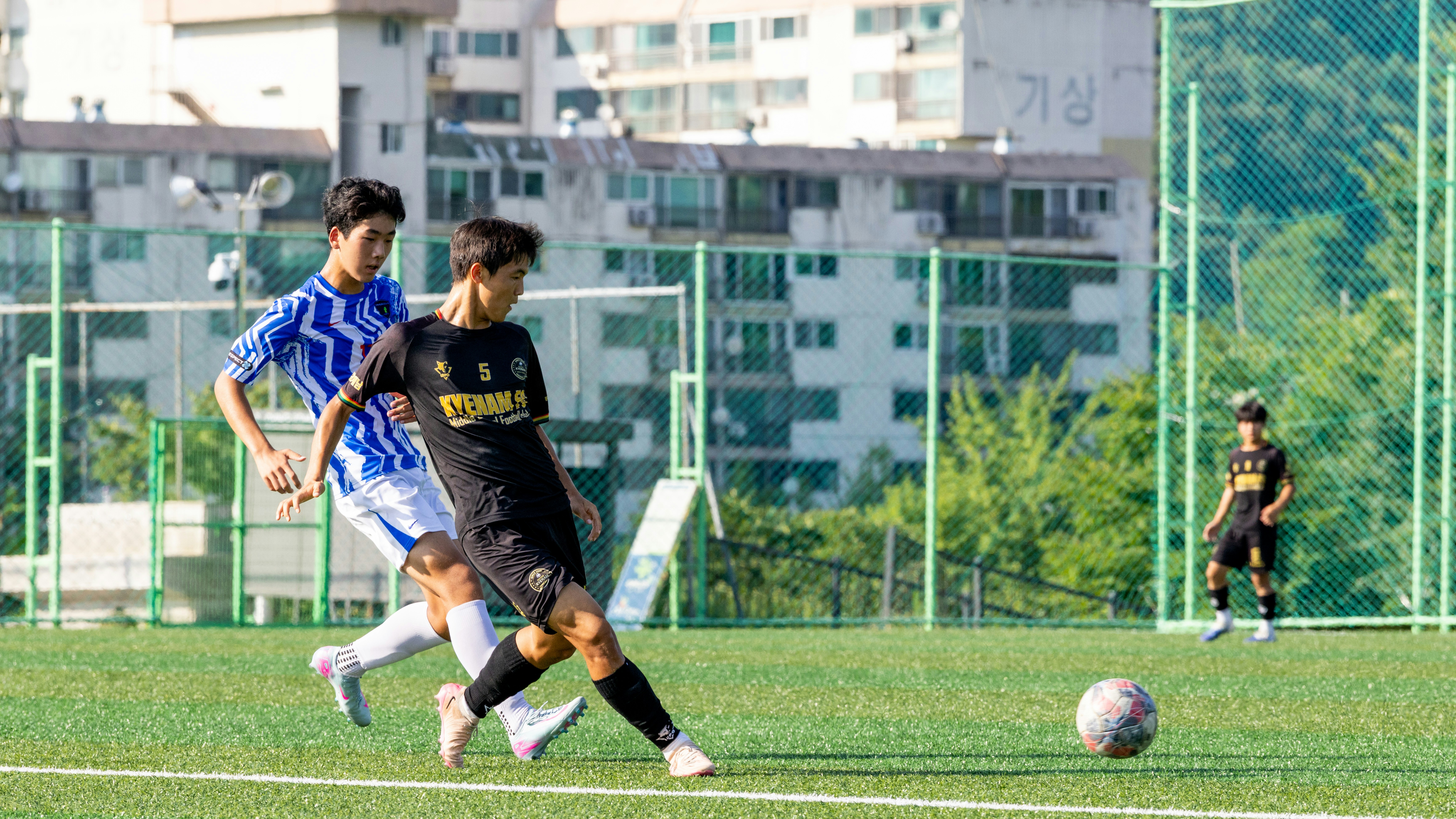 Young men play soccer on a grassy field.