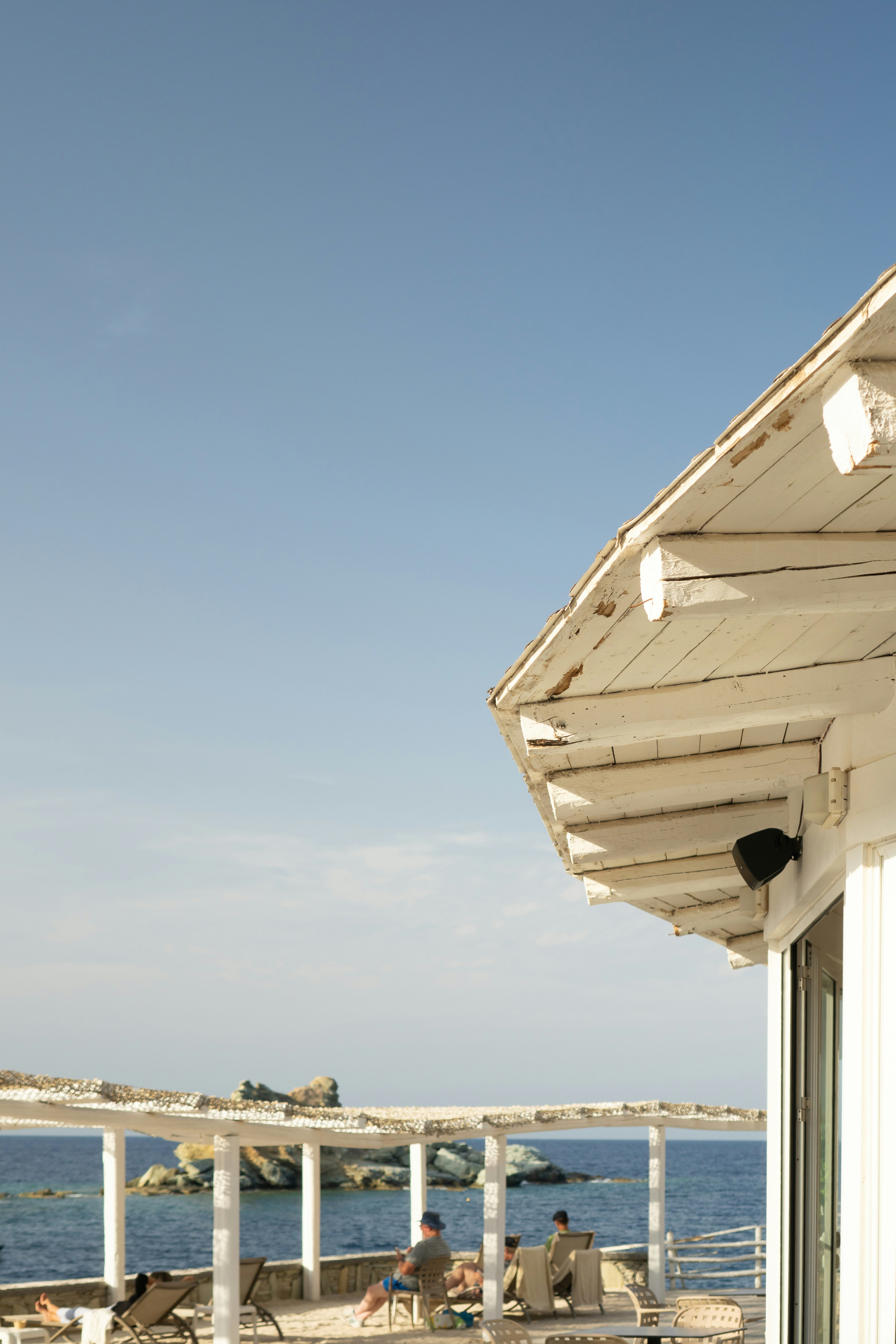 People relaxing by the sea under white canopy.