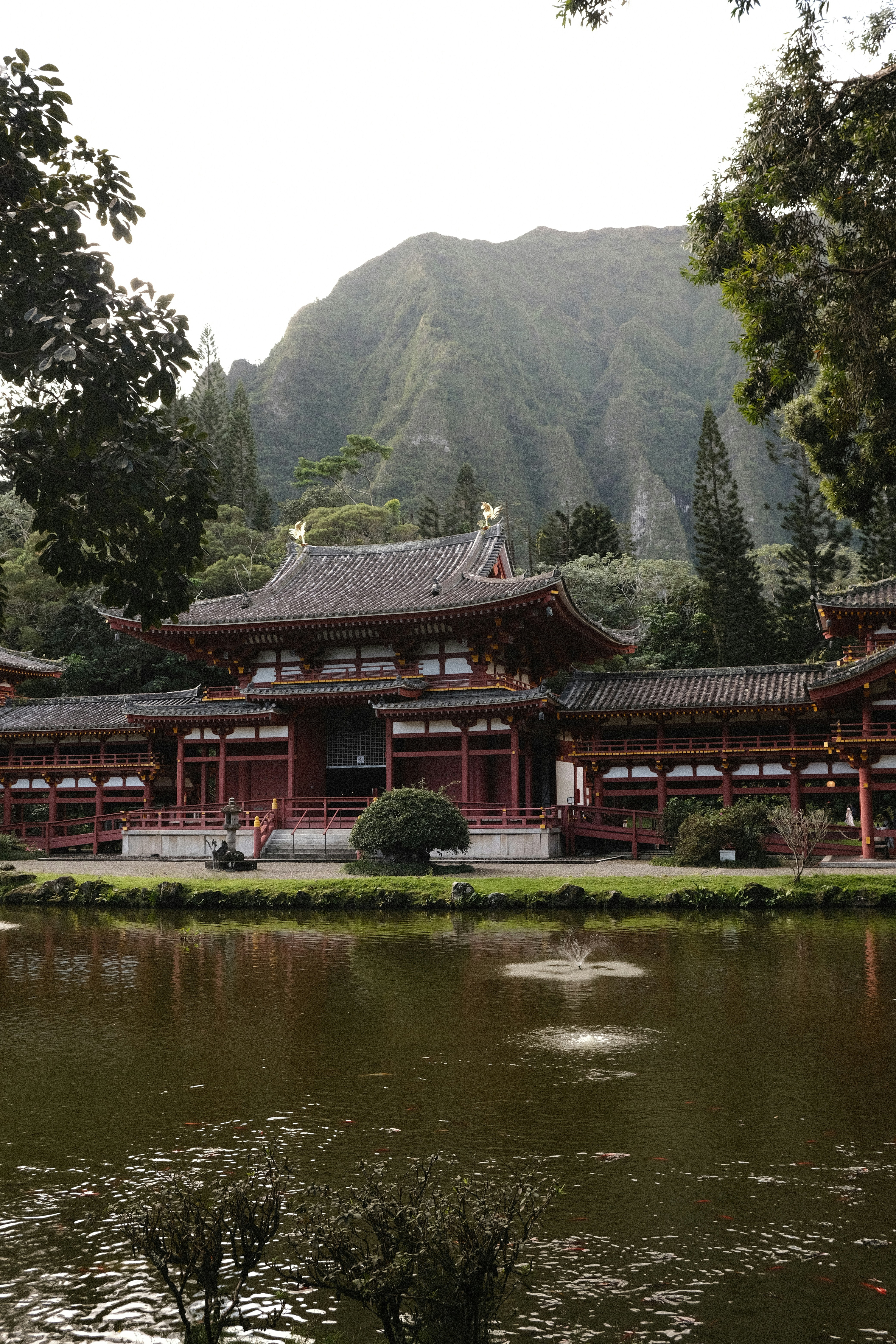 Traditional japanese temple with a pond and mountains.