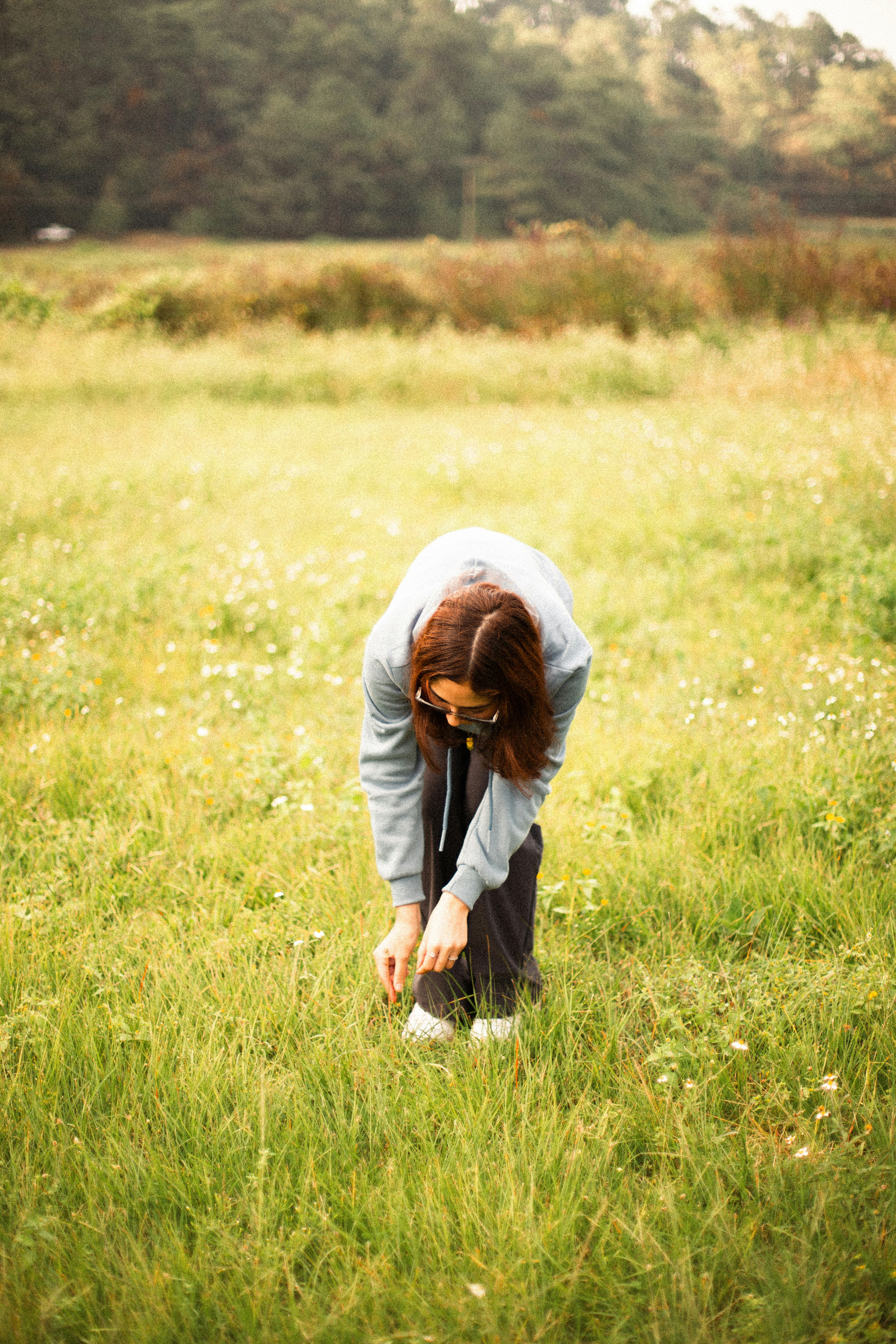 A woman bending down in a grassy field.